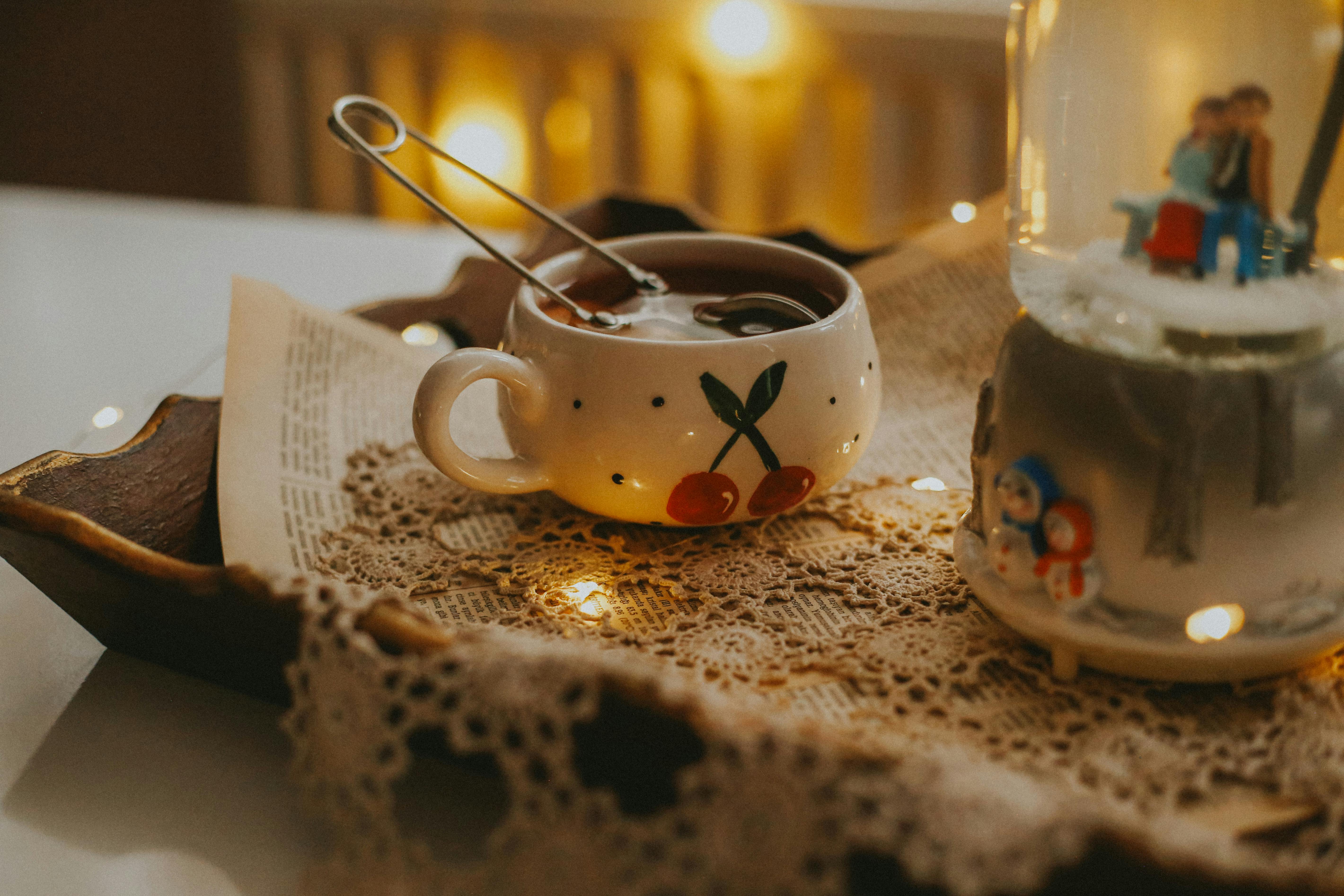 Cozy Winter Setting with Hot Beverage and Snow Globe · Free Stock Photo
