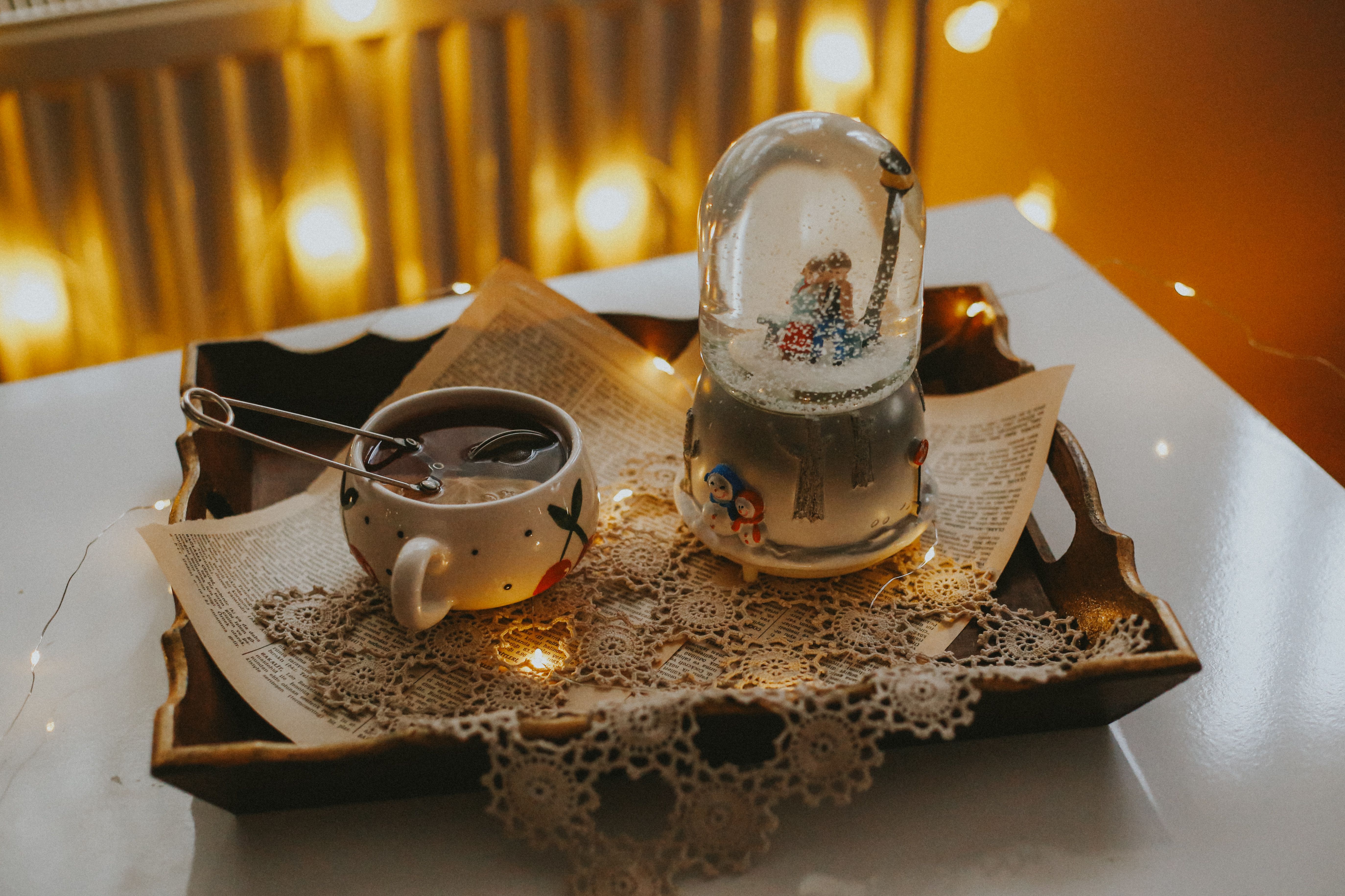 Cozy Winter Scene with Tea and Snow Globe · Free Stock Photo