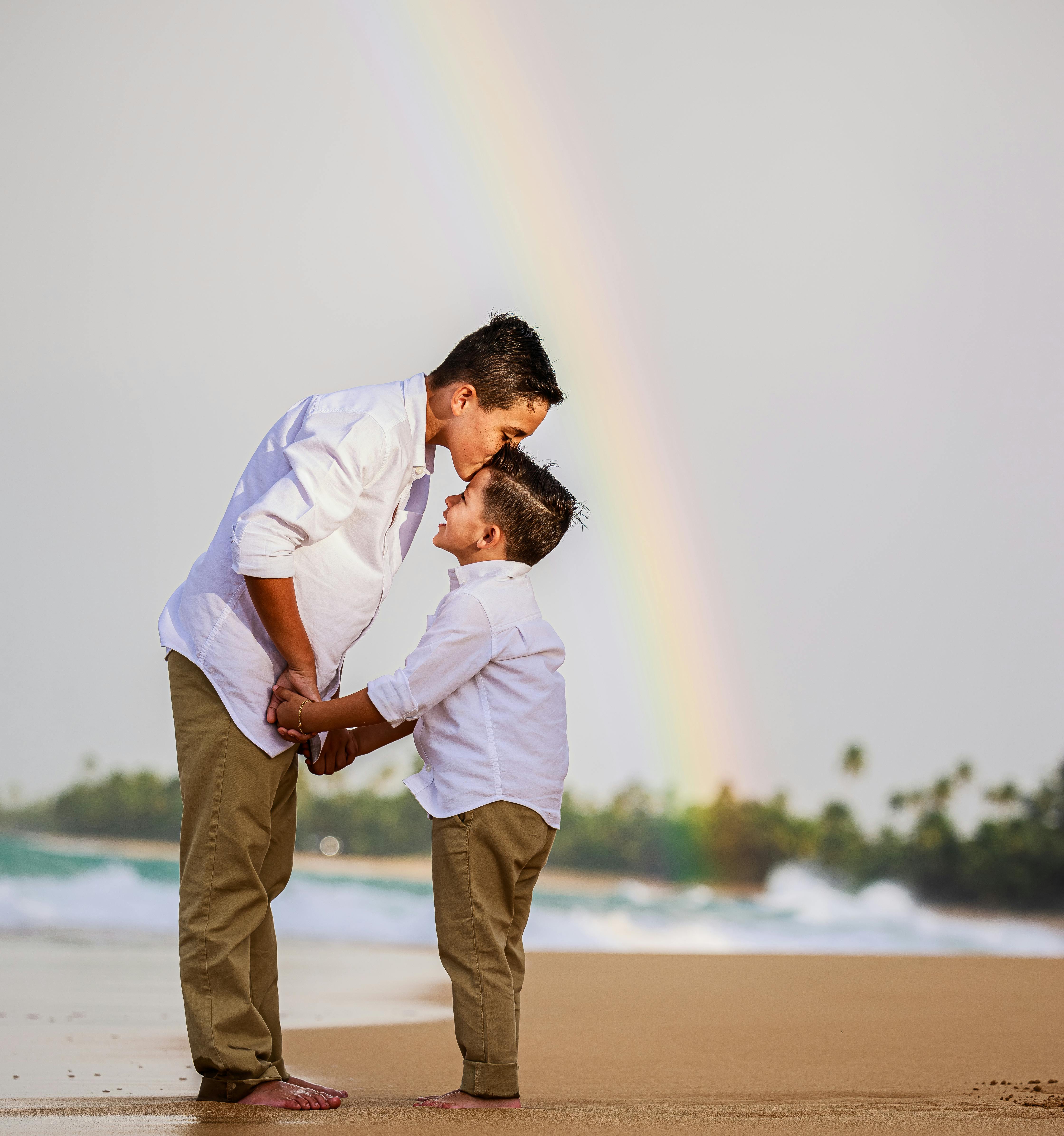 Father and Son Embracing on Beach with Rainbow · Free Stock Photo