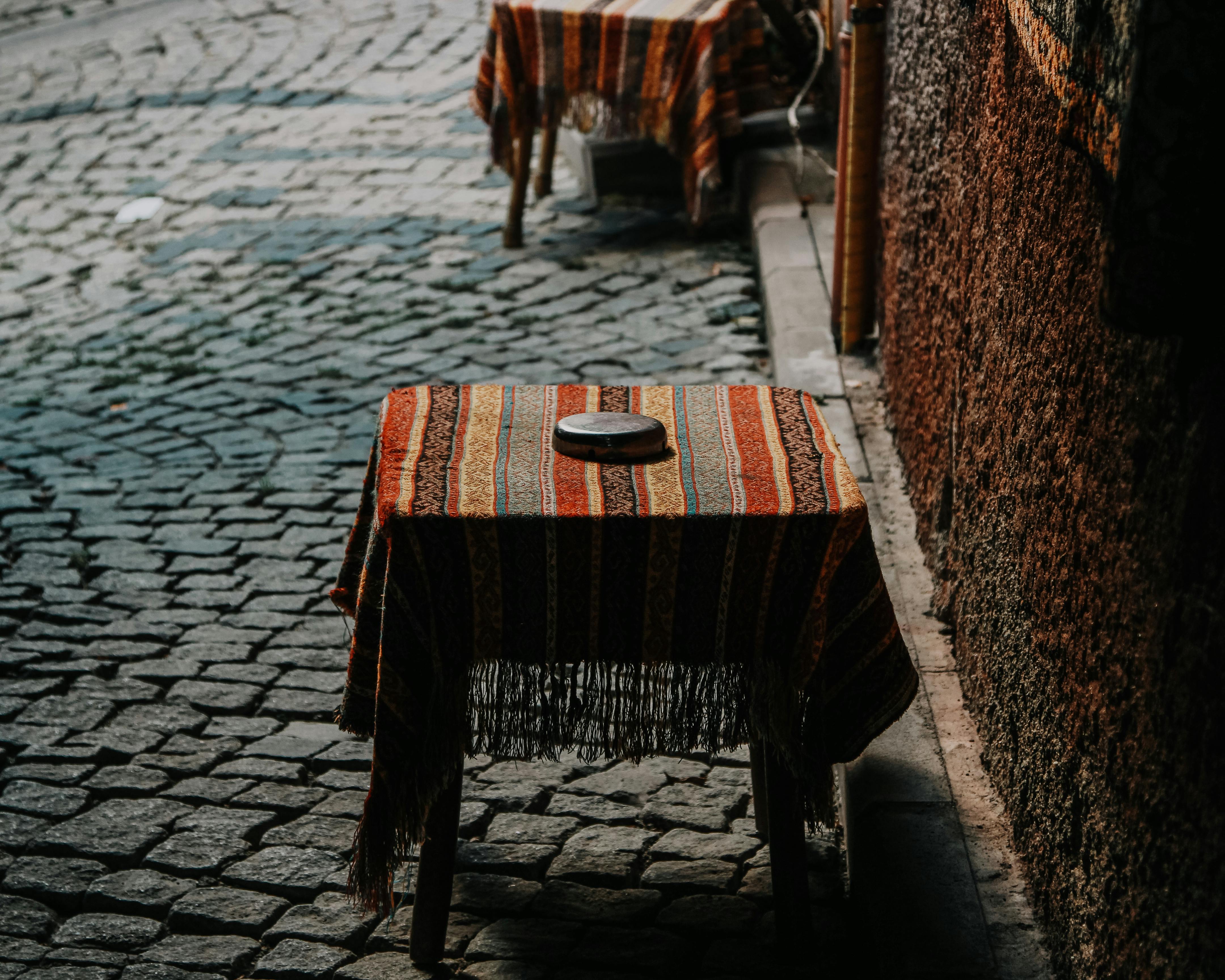 Cozy Outdoor Table with Striped Tablecloth on Cobblestone Street · Free ...