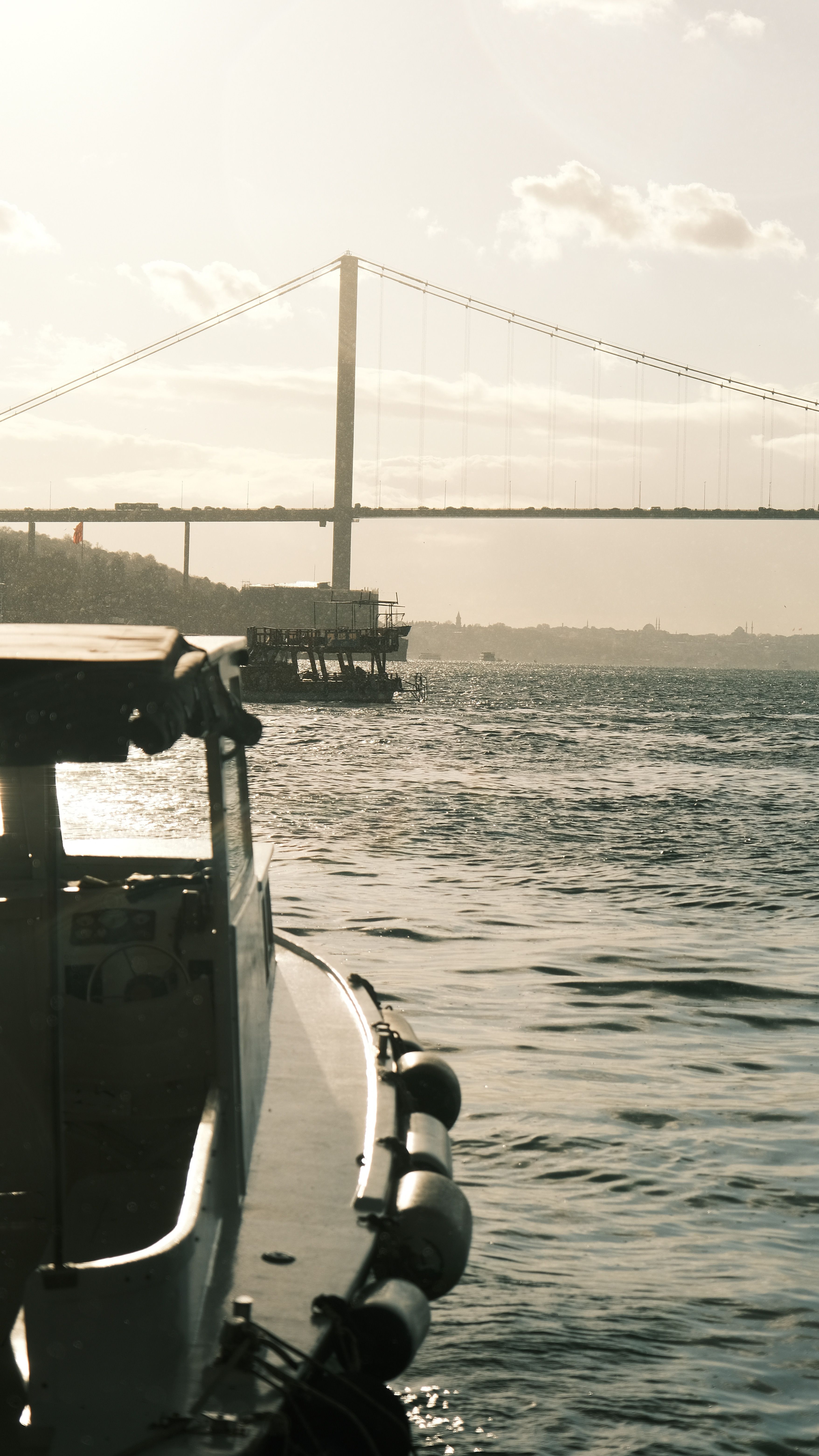 Boat Sailing Under a Suspension Bridge at Sunset · Free Stock Photo