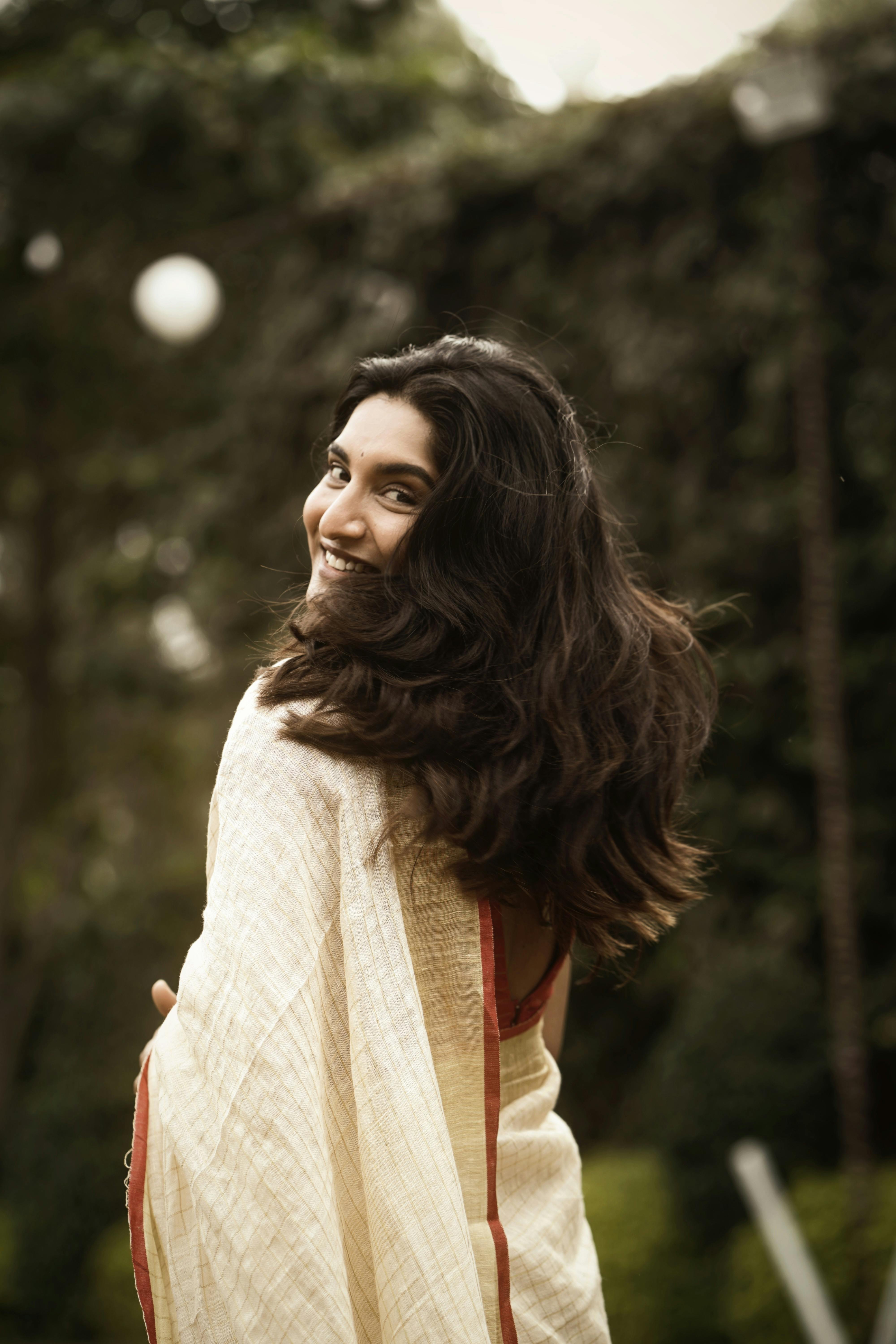 Smiling Woman in Traditional White Saree Outdoors · Free Stock Photo