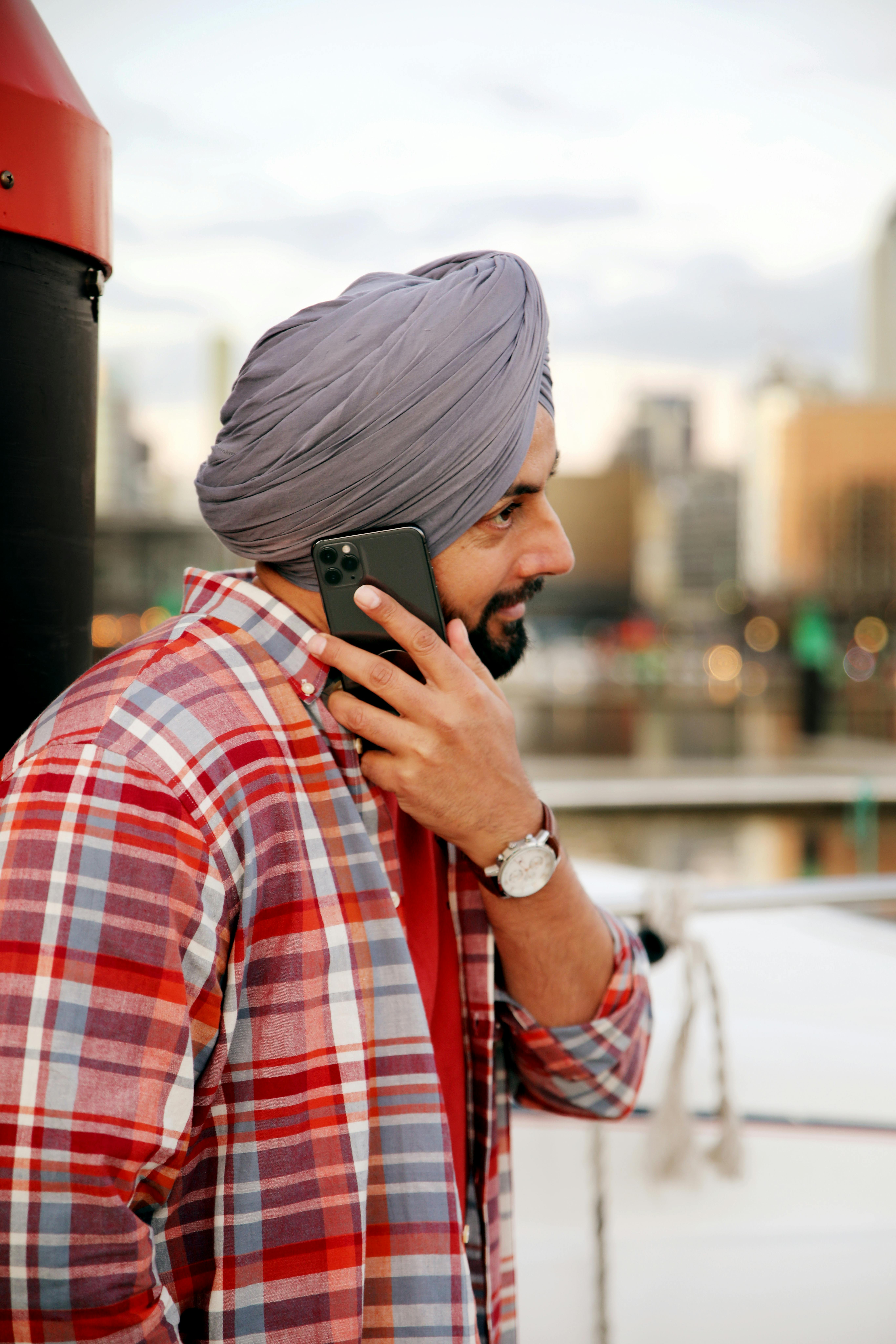 Man with turban using phone outdoors Australia · Free Stock Photo