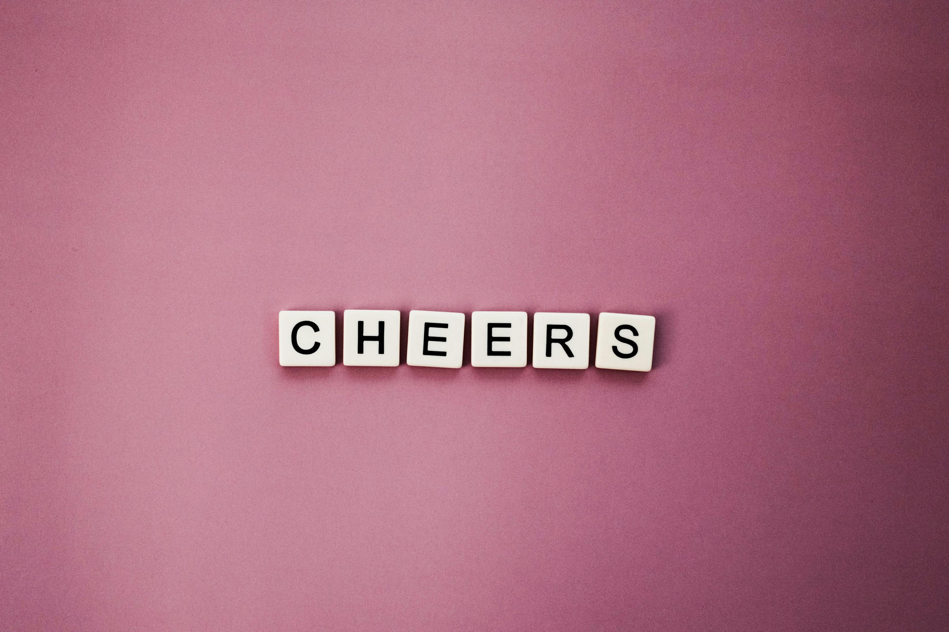 Creative Cheers Message with Letter Tiles on Pink Background · Free ...