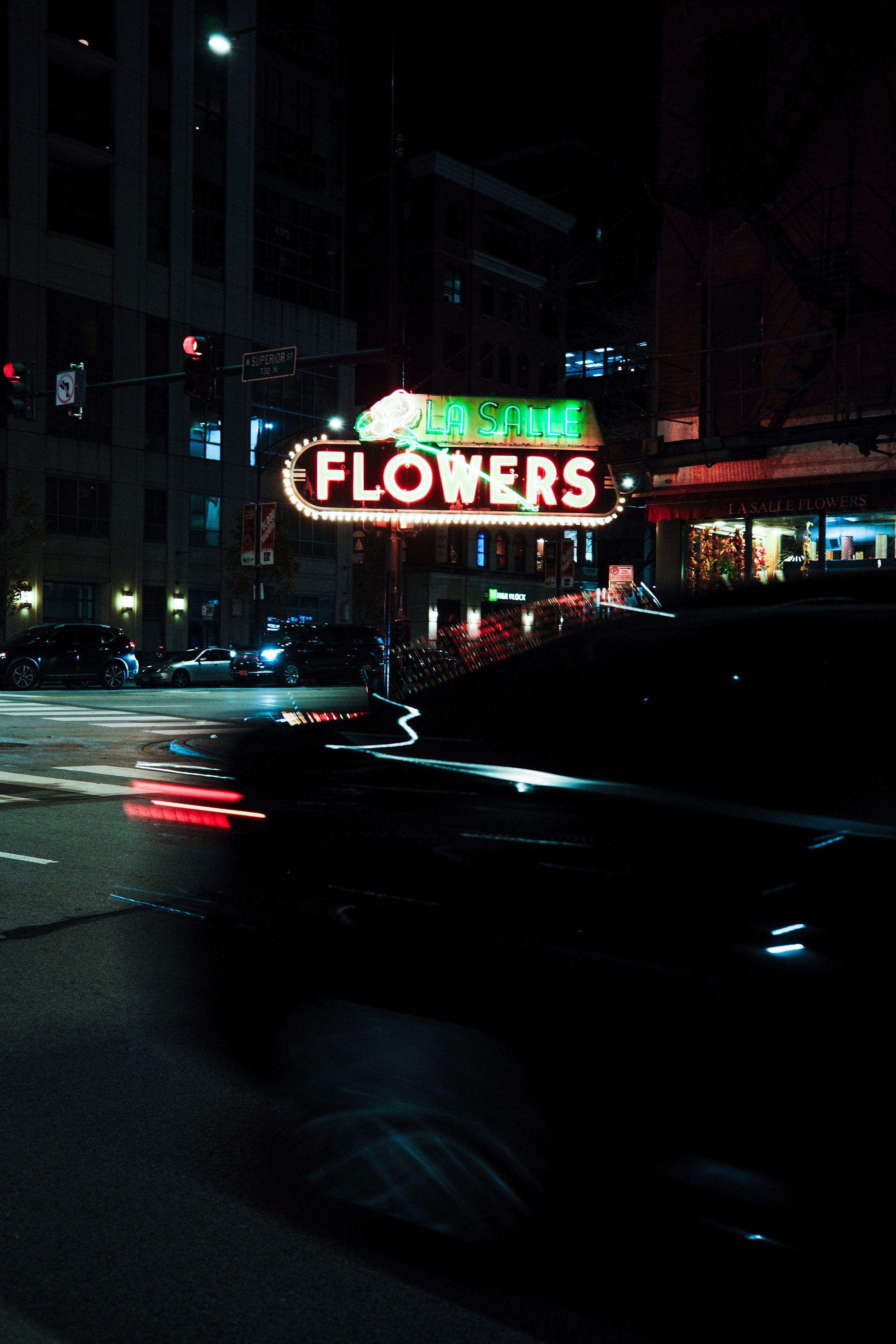 Nighttime Urban Scene with Neon Flower Sign · Free Stock Photo