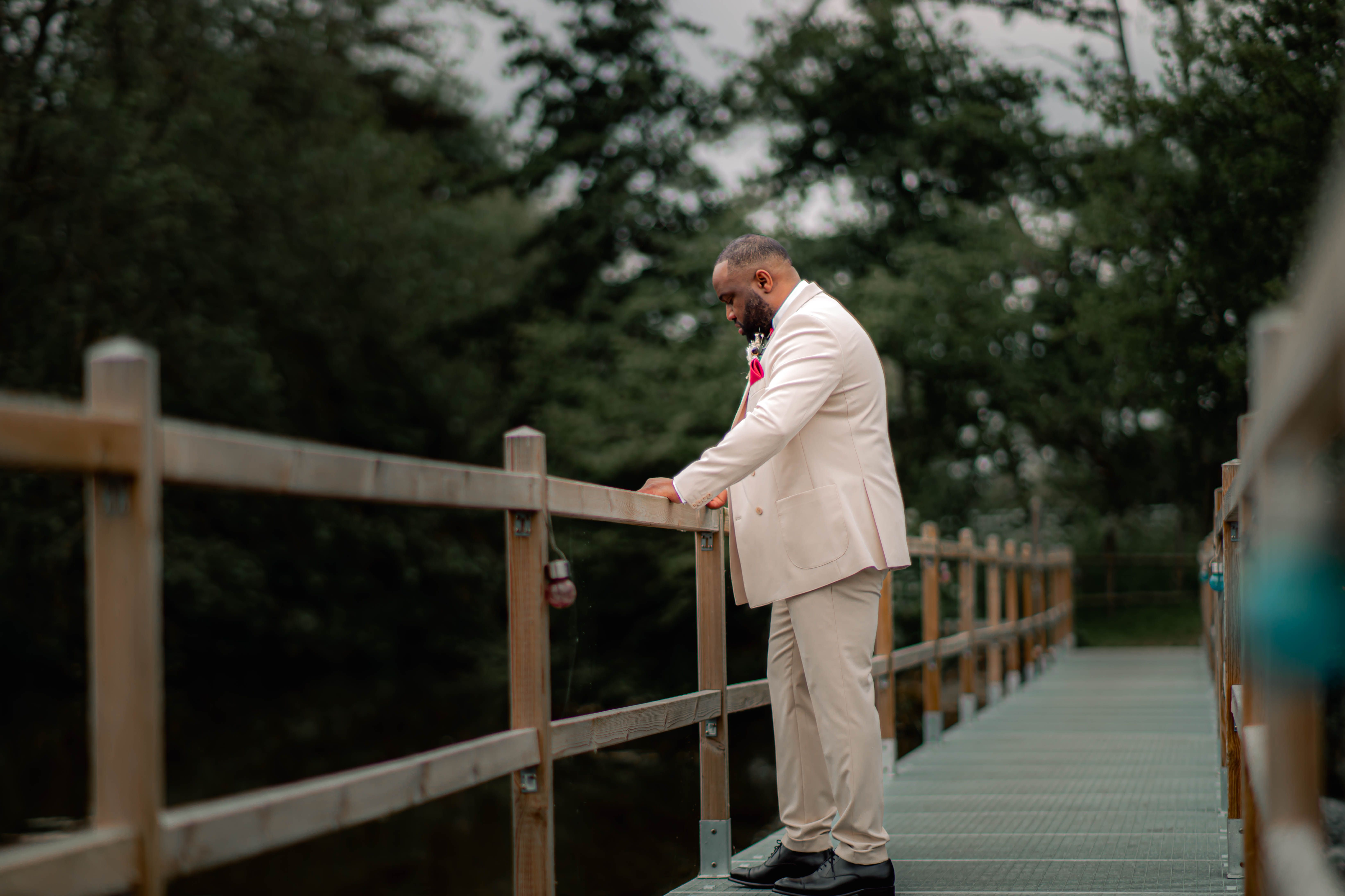 Thoughtful Man in White Suit on Bridge Outdoors · Free Stock Photo