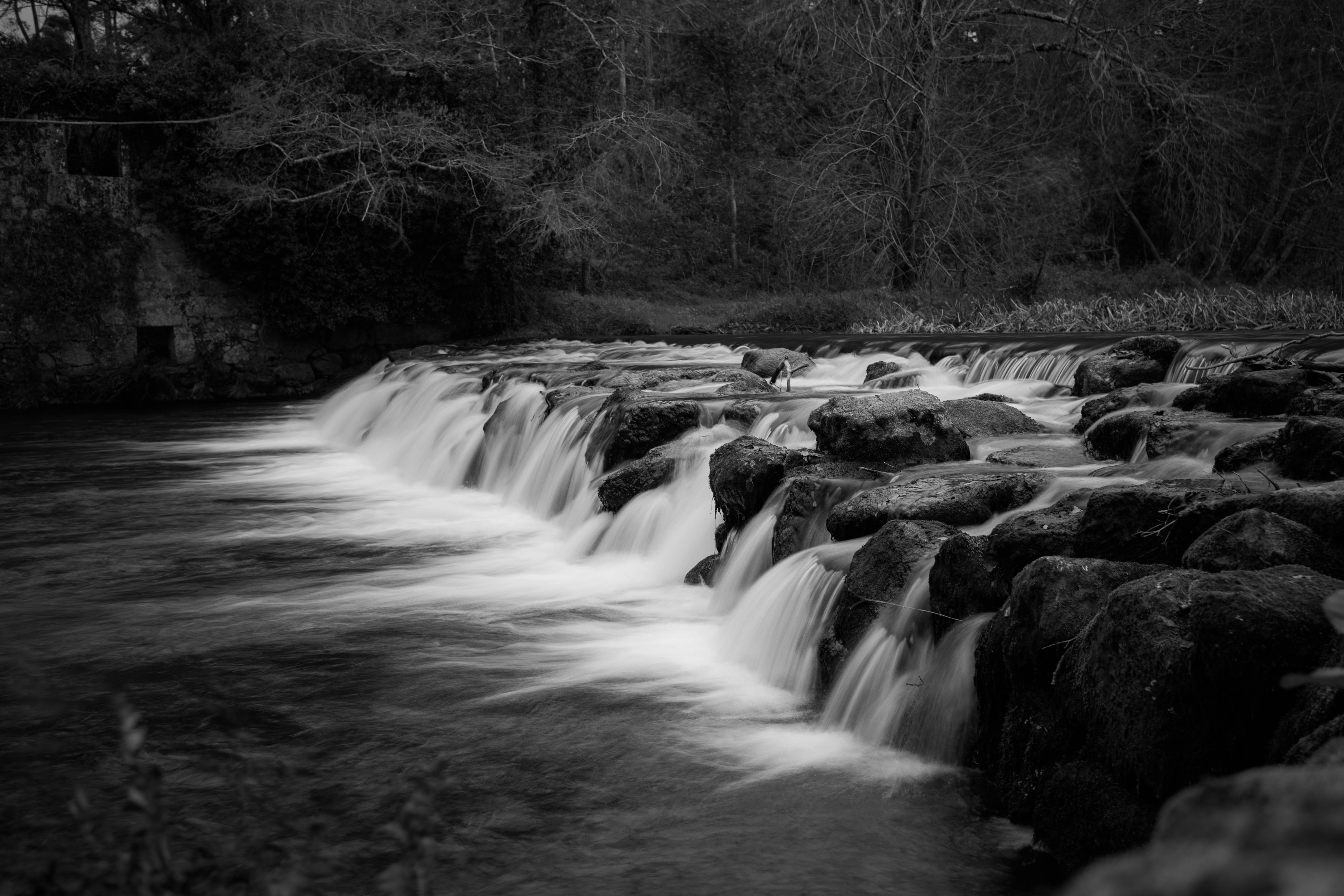 Serene Black and White River Scene with Waterfall · Free Stock Photo