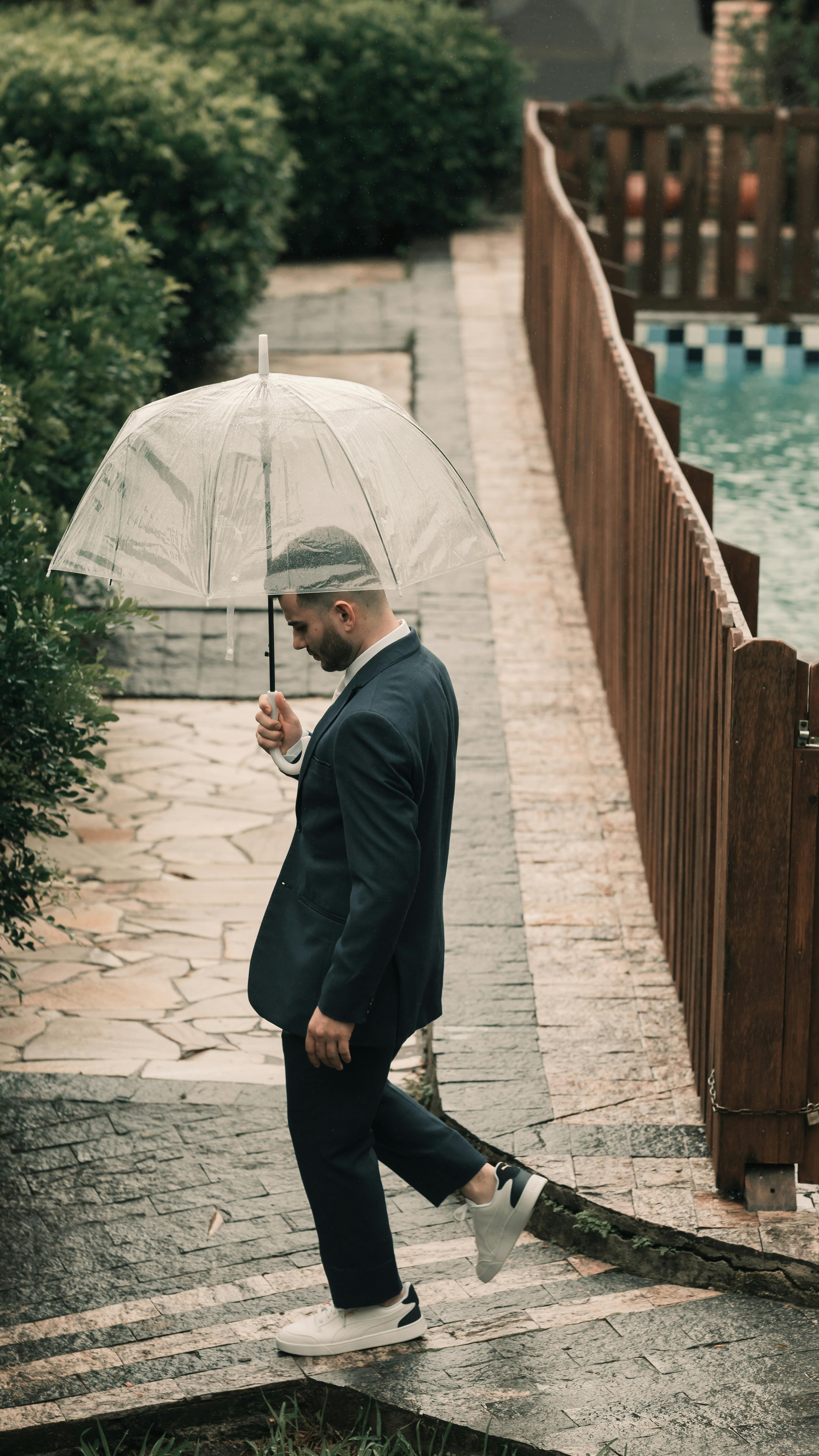 Man Walking with Umbrella by Poolside · Free Stock Photo