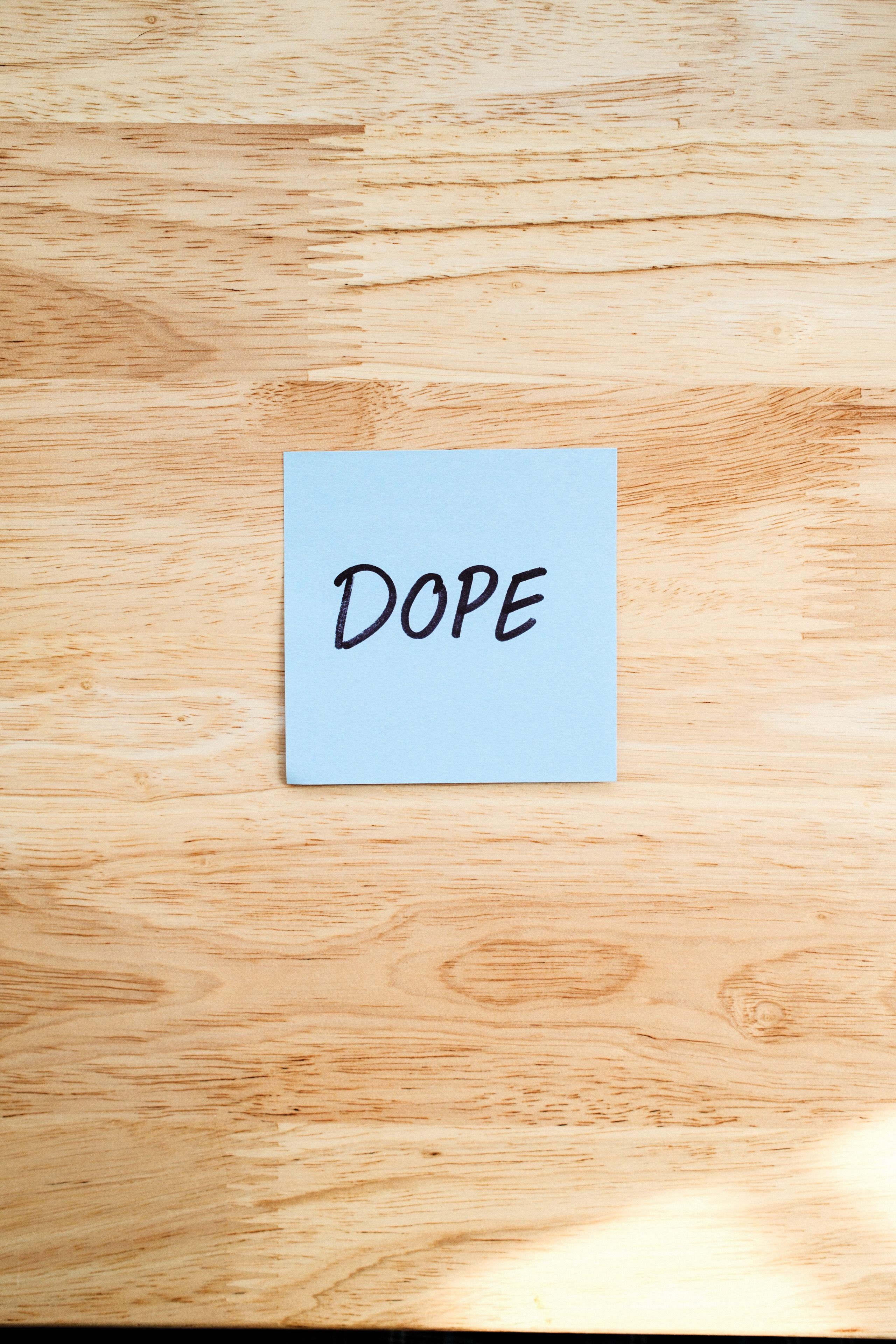 Minimalist Sticky Note with "Dope" Text on Wood · Free Stock Photo