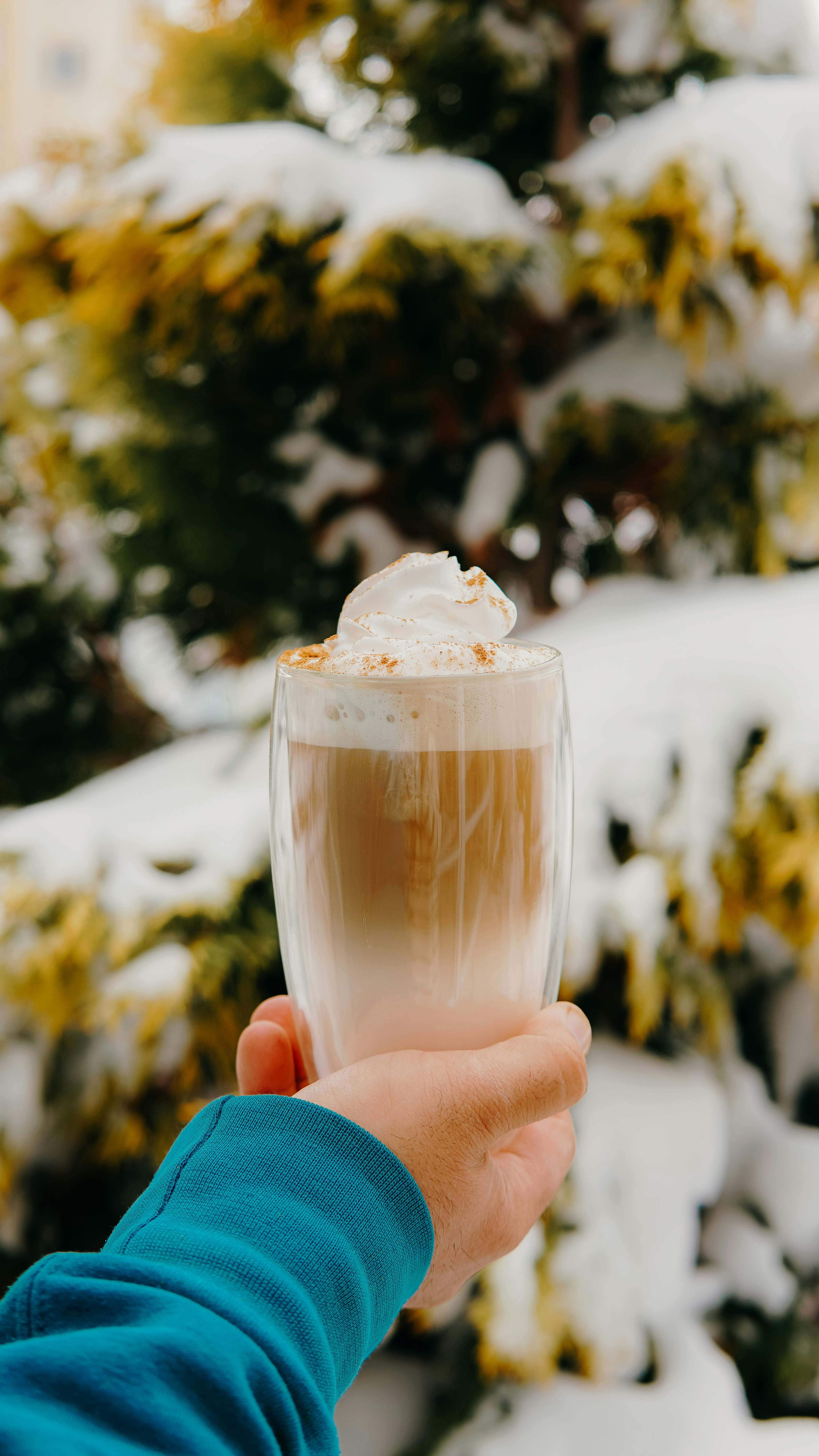Warm Latte with Cream Held in Winter Snow Scene · Free Stock Photo