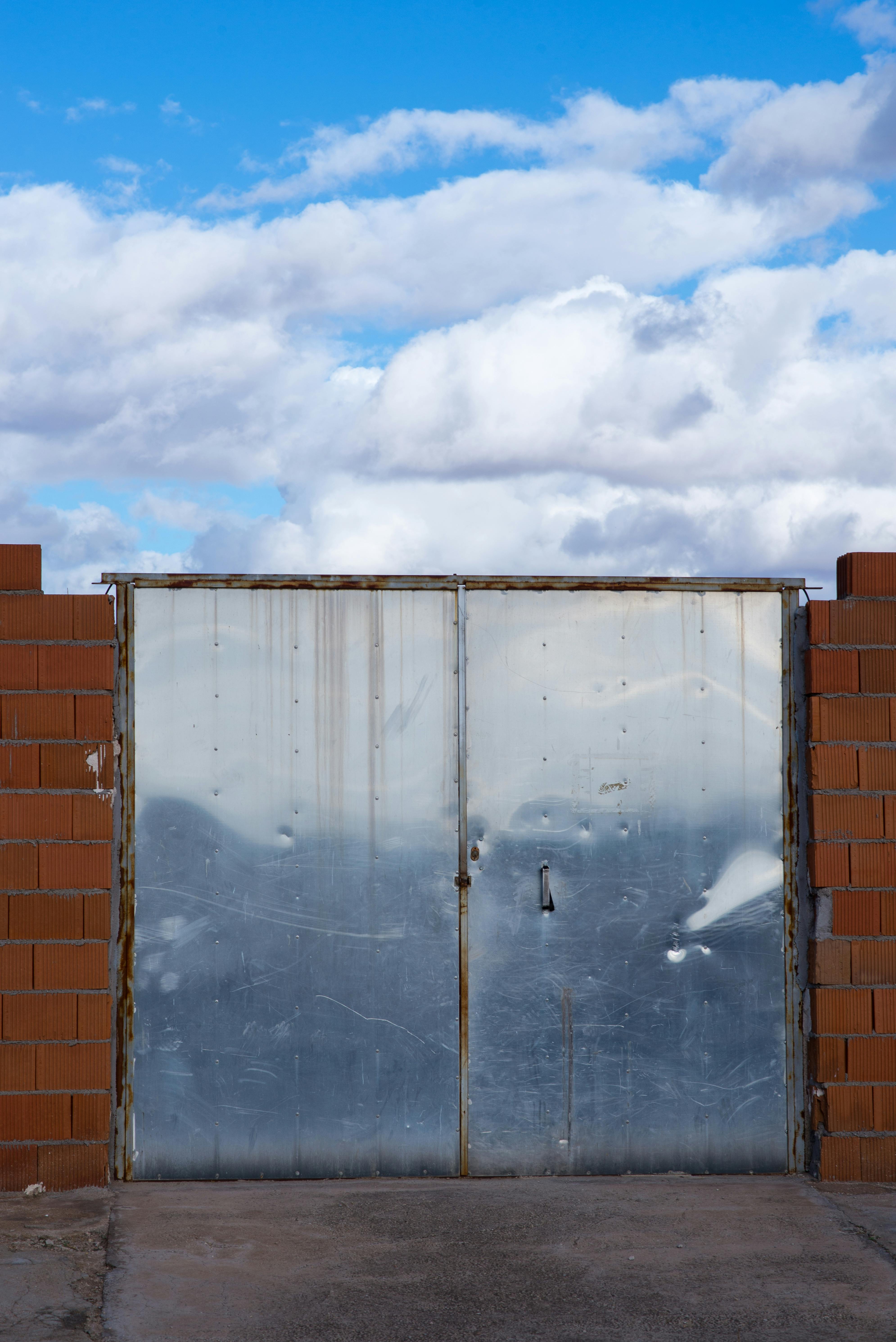 Rustic Metal Gate Against Cloudy Blue Sky · Free Stock Photo
