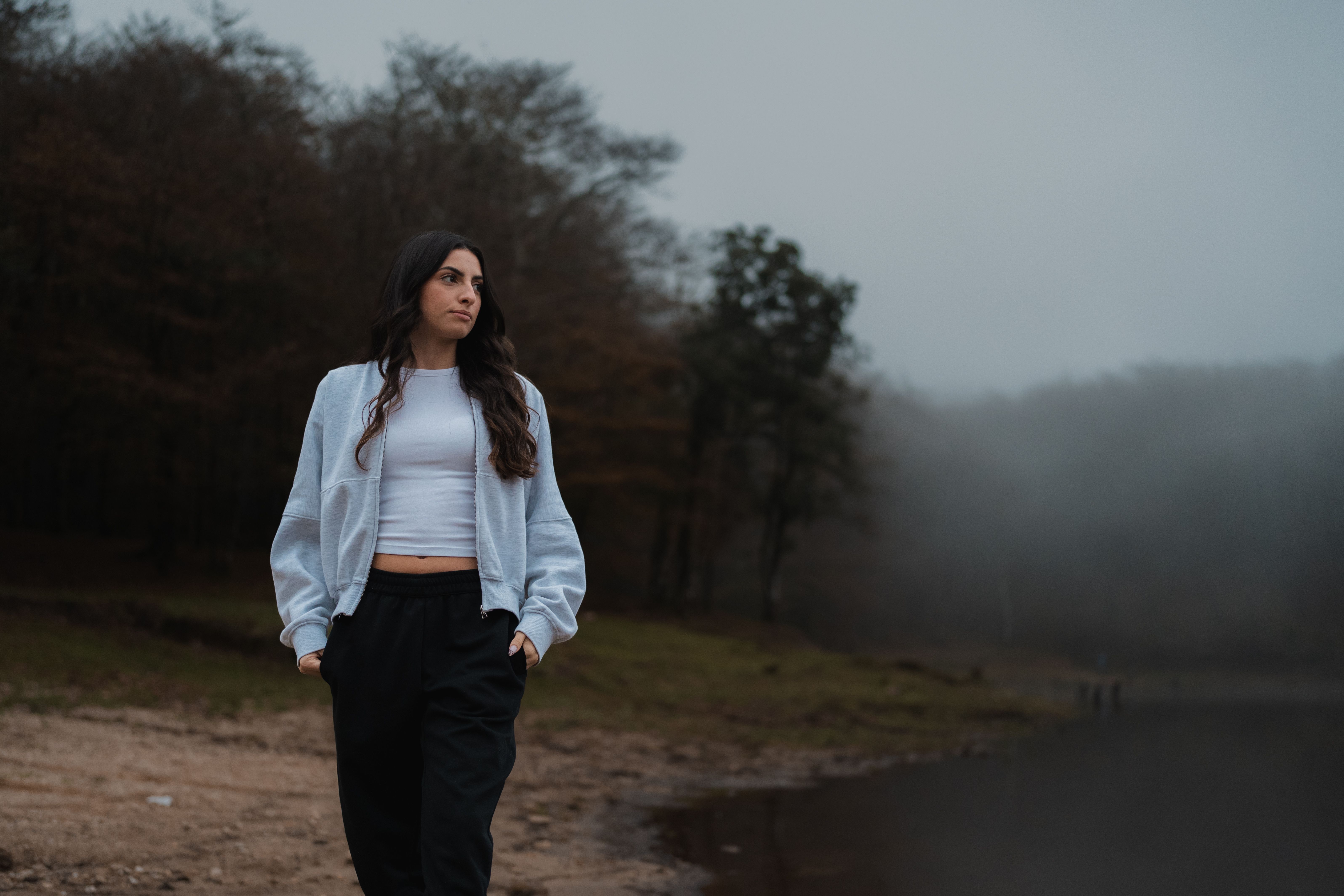 Woman Walking Along Misty Lakeside Trail · Free Stock Photo