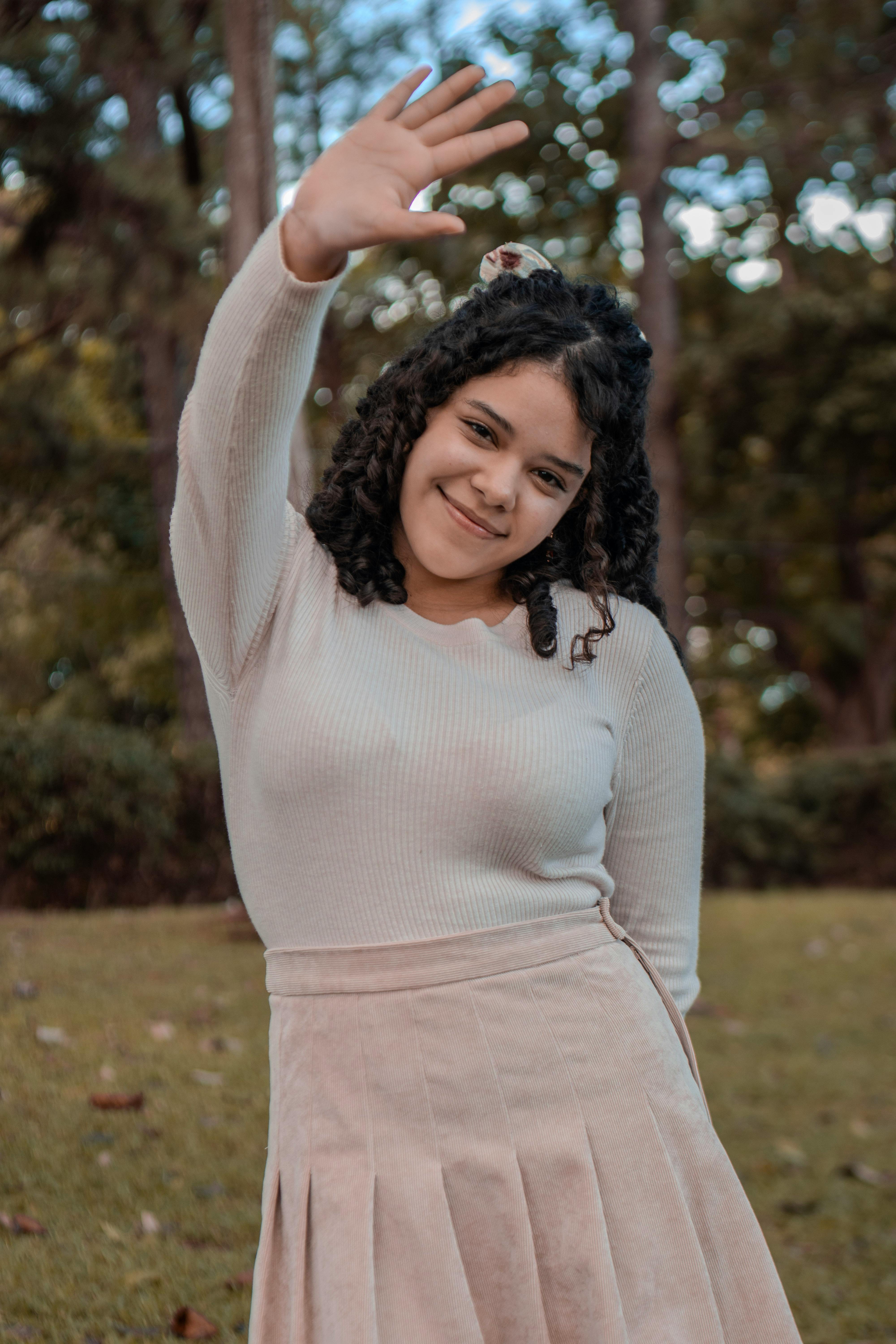 Smiling Woman Waving in a Park Setting · Free Stock Photo