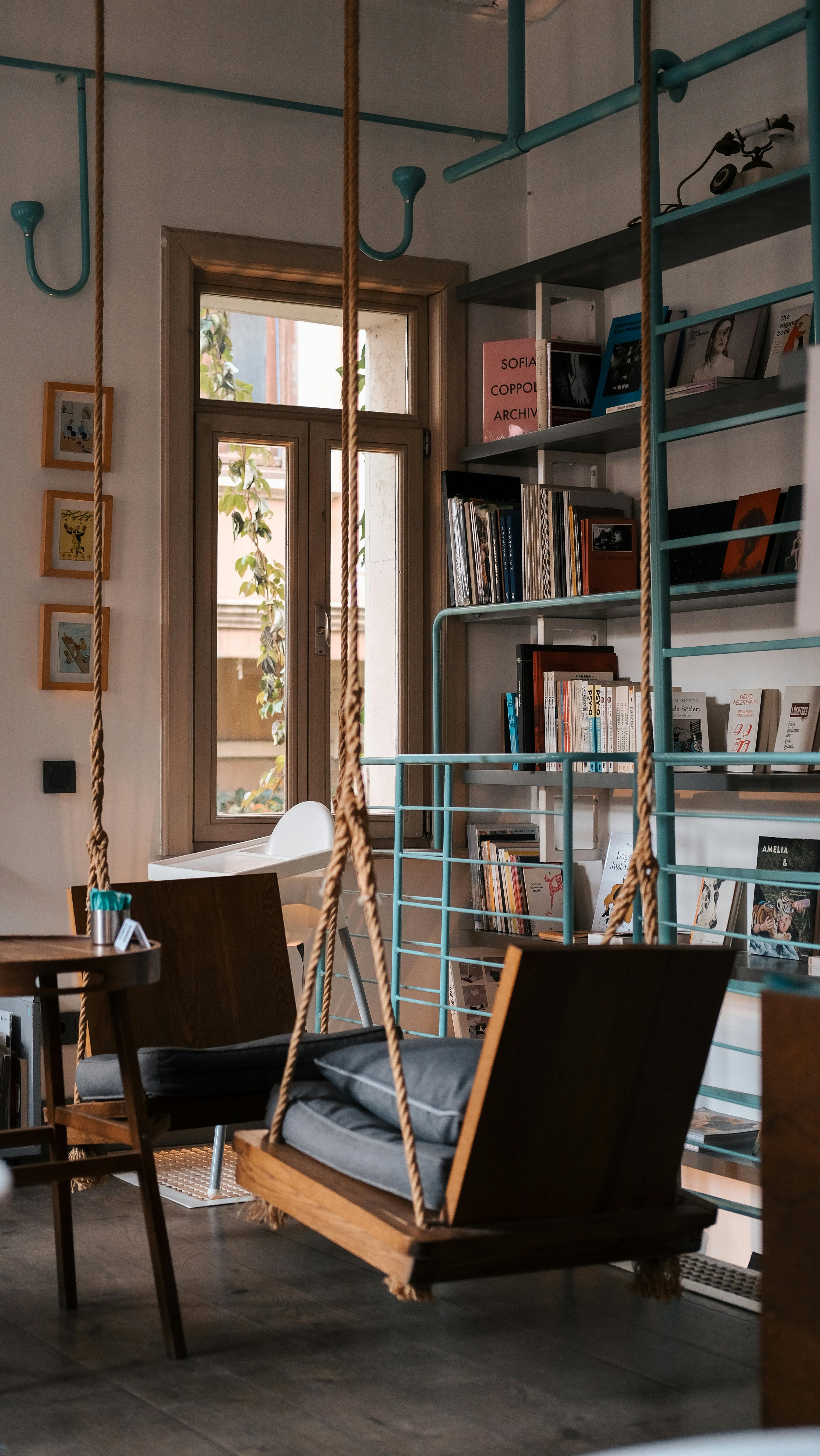 Cozy Interior with Swinging Chairs and Bookshelves · Free Stock Photo