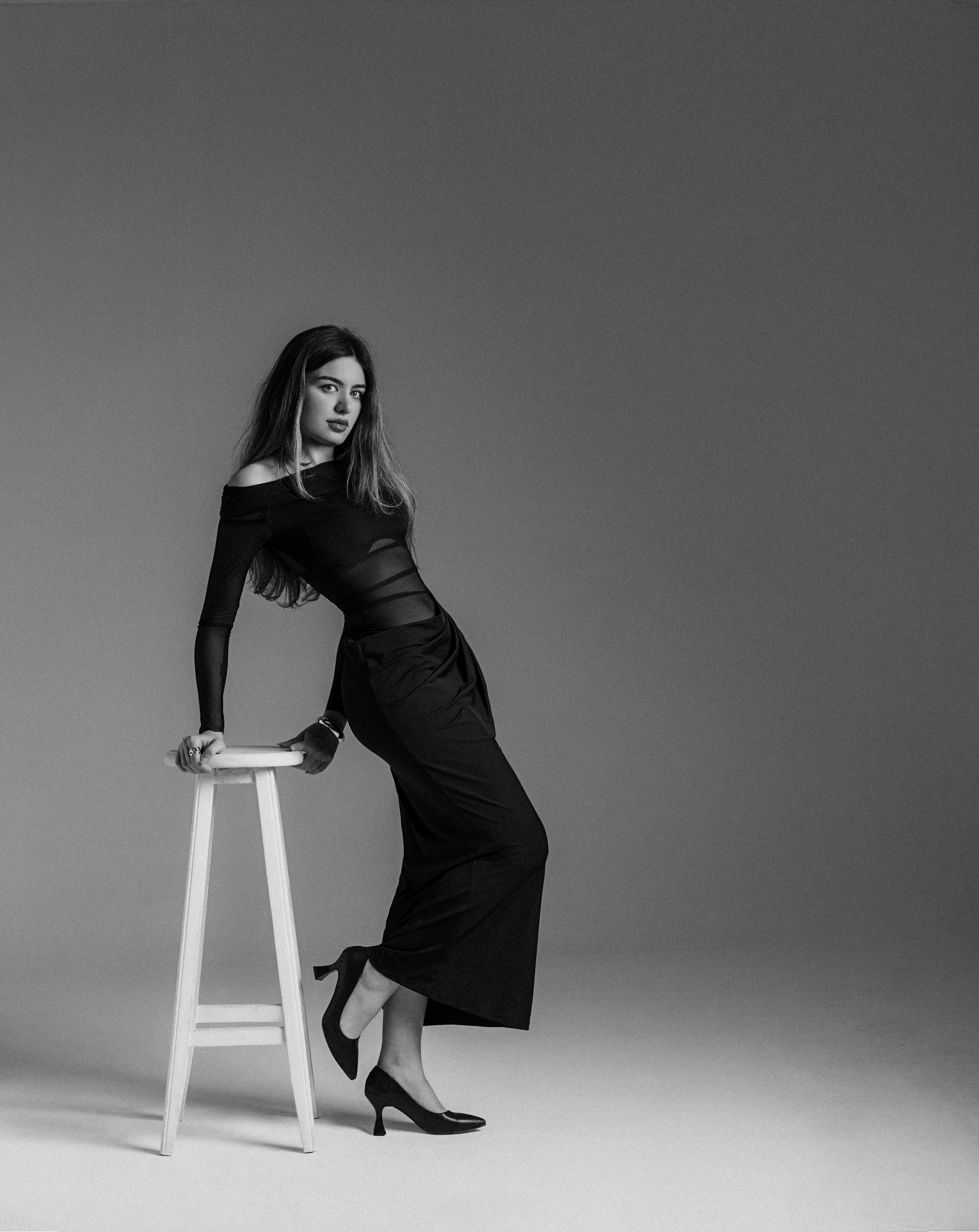 Elegant Woman in Black Outfit Leaning on Stool · Free Stock Photo