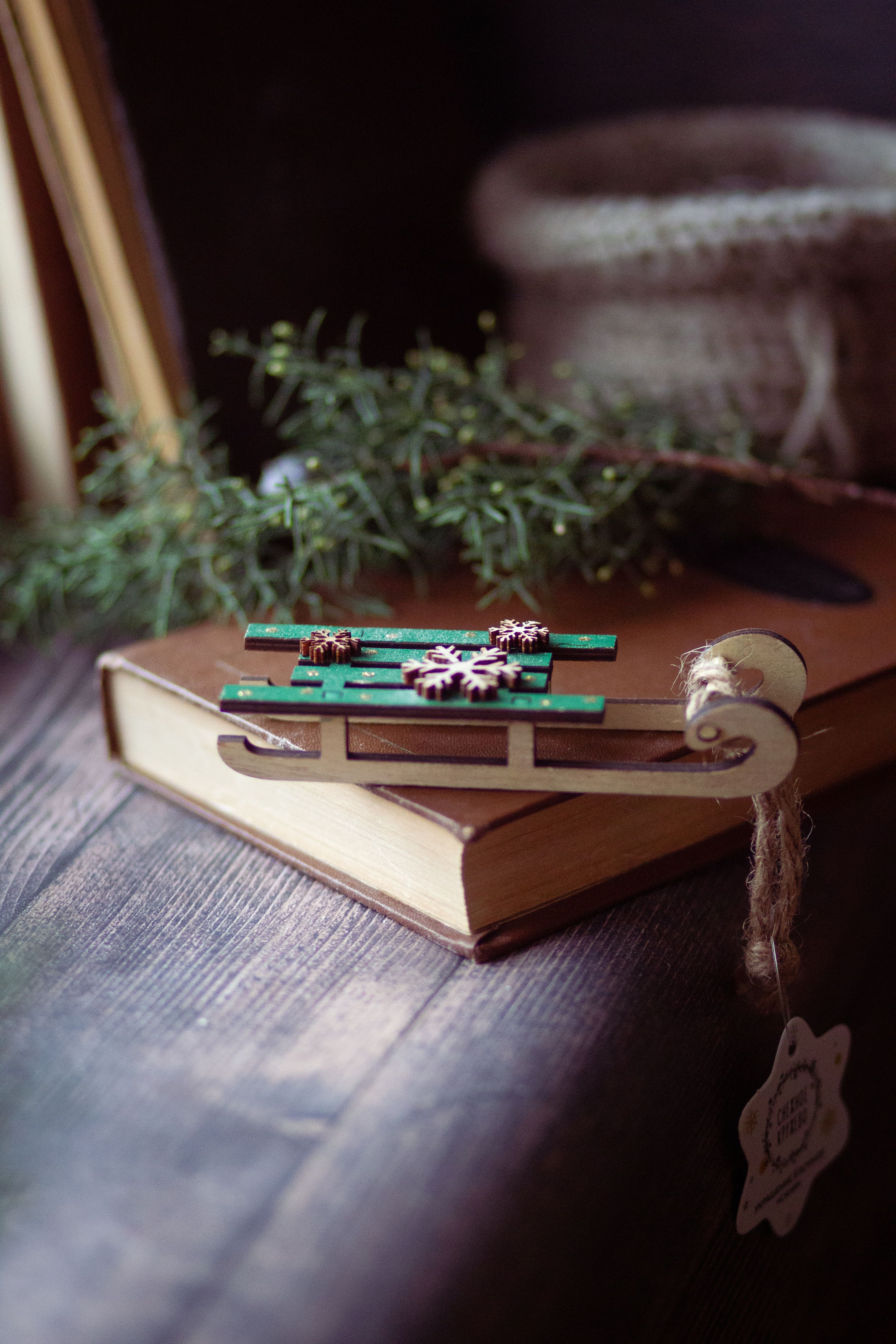 Rustic Christmas Sled Ornament on Wooden Book · Free Stock Photo