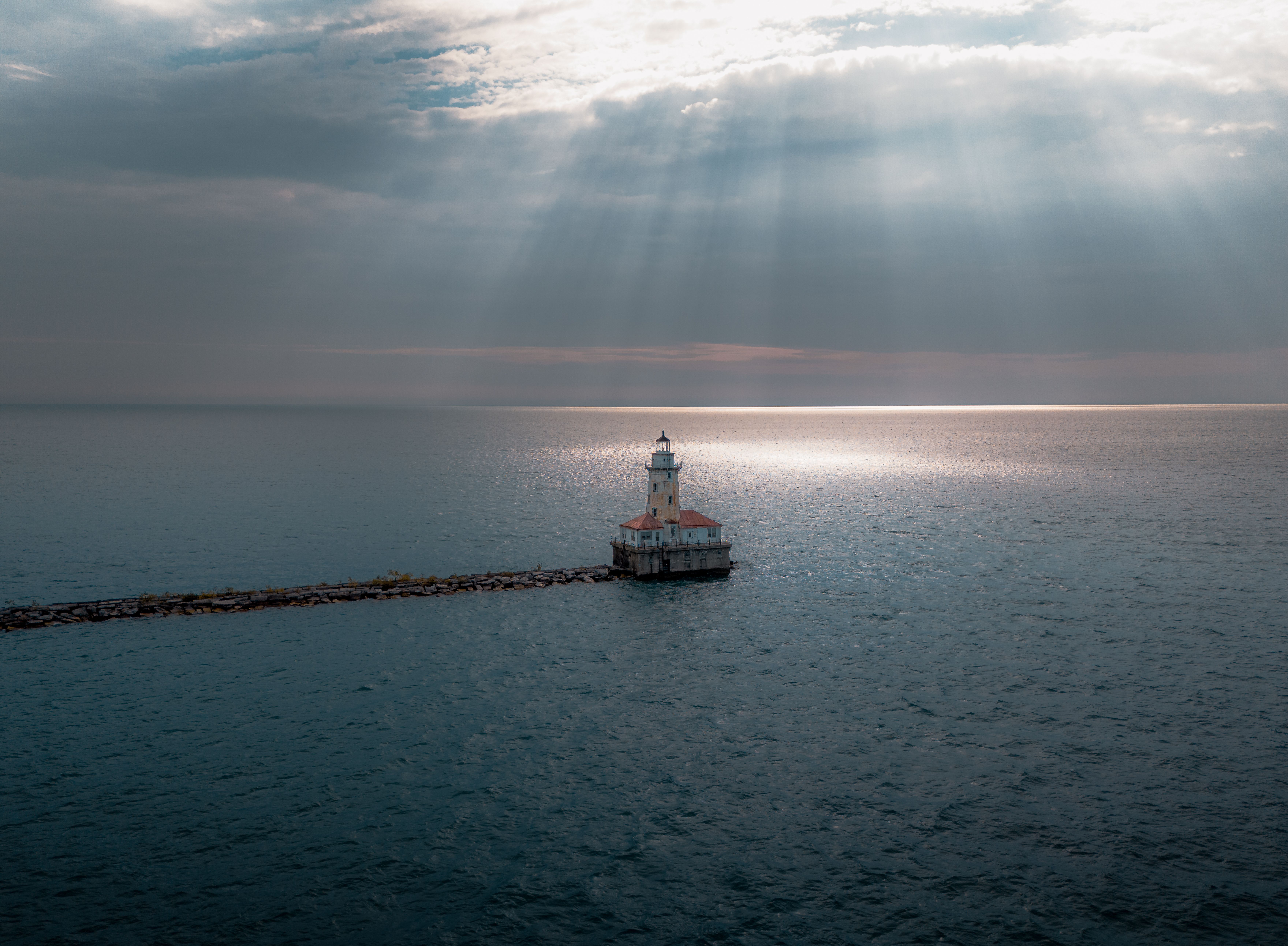 Dramatic Lighthouse Under Cloudy Sky on Ocean · Free Stock Photo