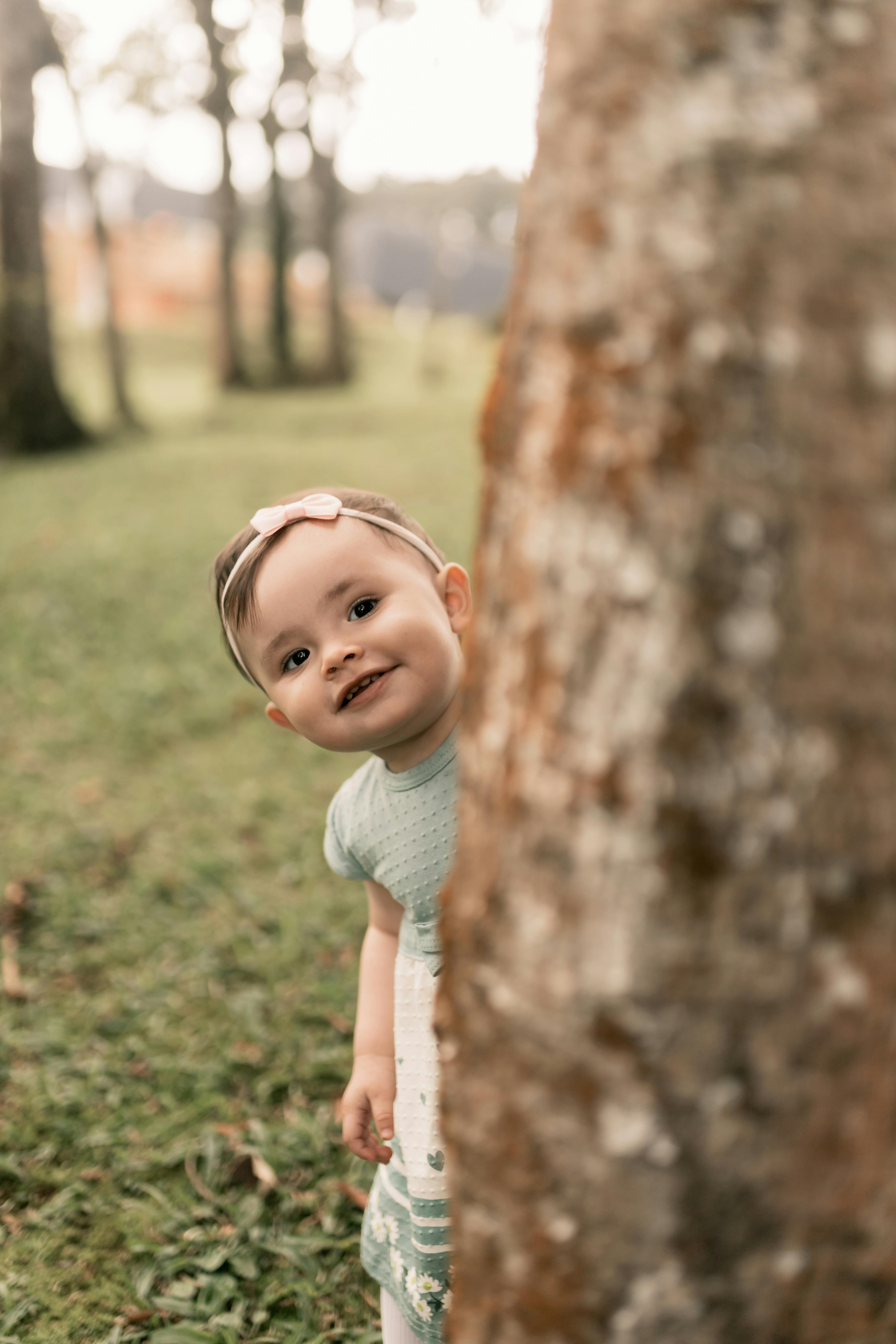 Adorable Child Peeking Behind Tree Outdoors · Free Stock Photo
