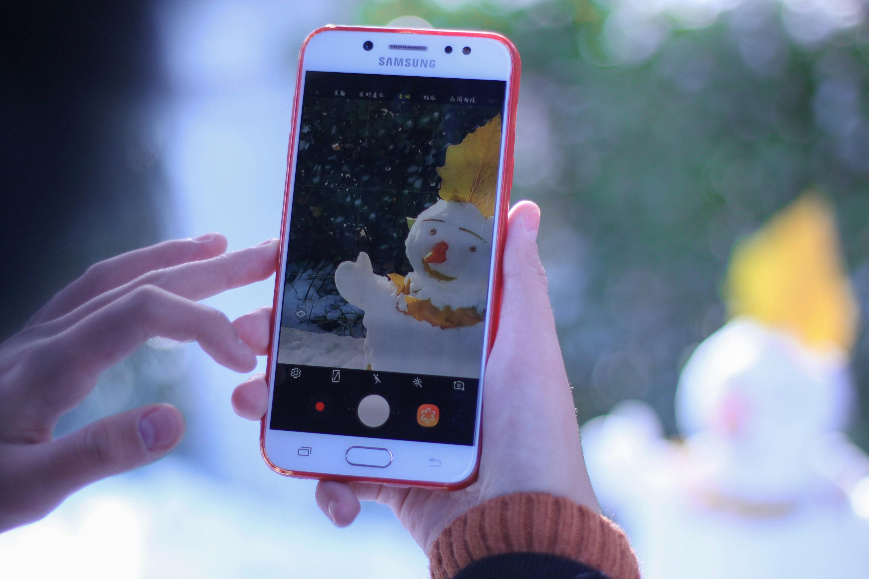 Smartphone Captures Snowman in Winter Scene · Free Stock Photo