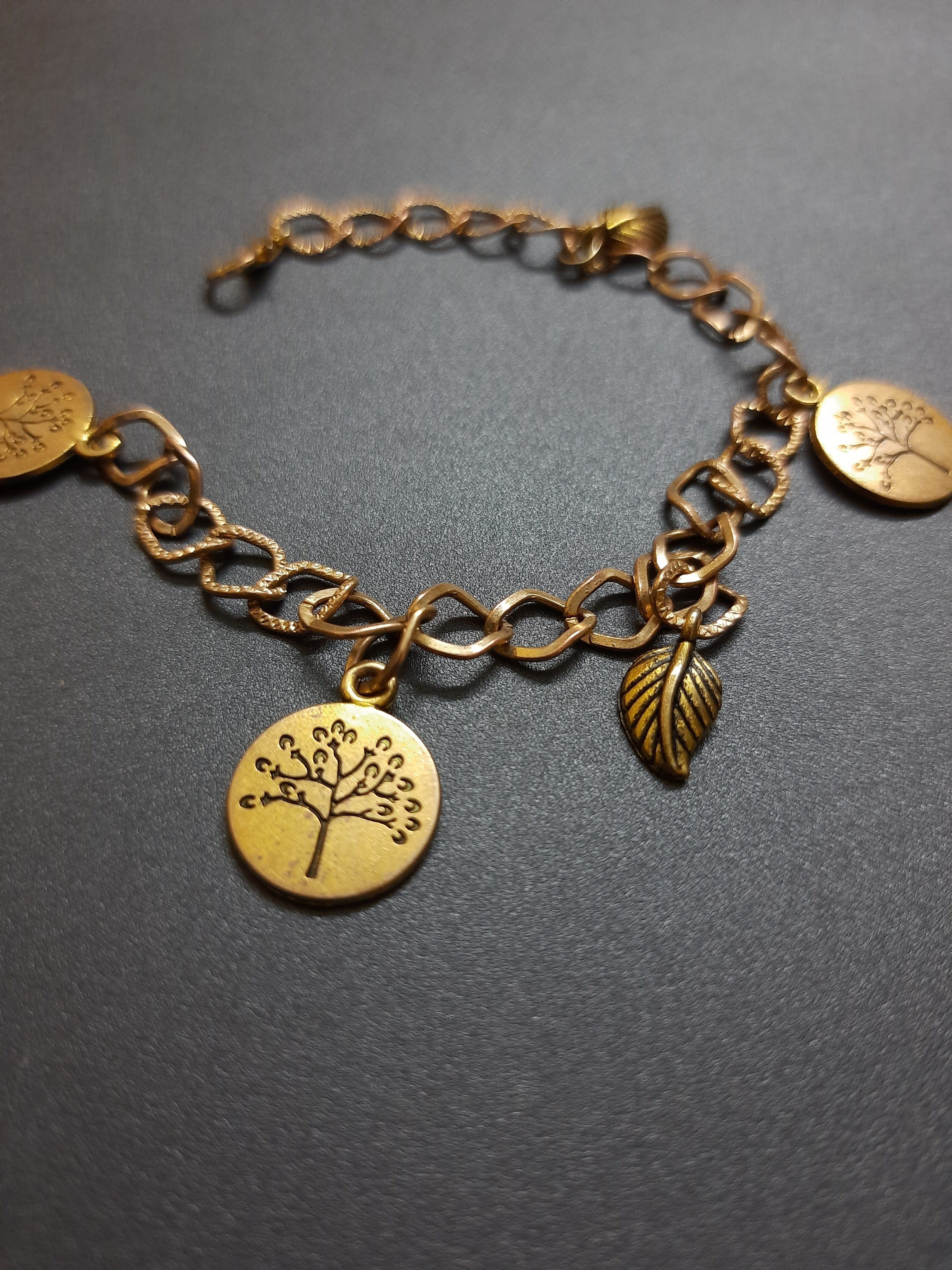 Elegant Gold Bracelet with Tree Charms on Black Surface · Free Stock Photo
