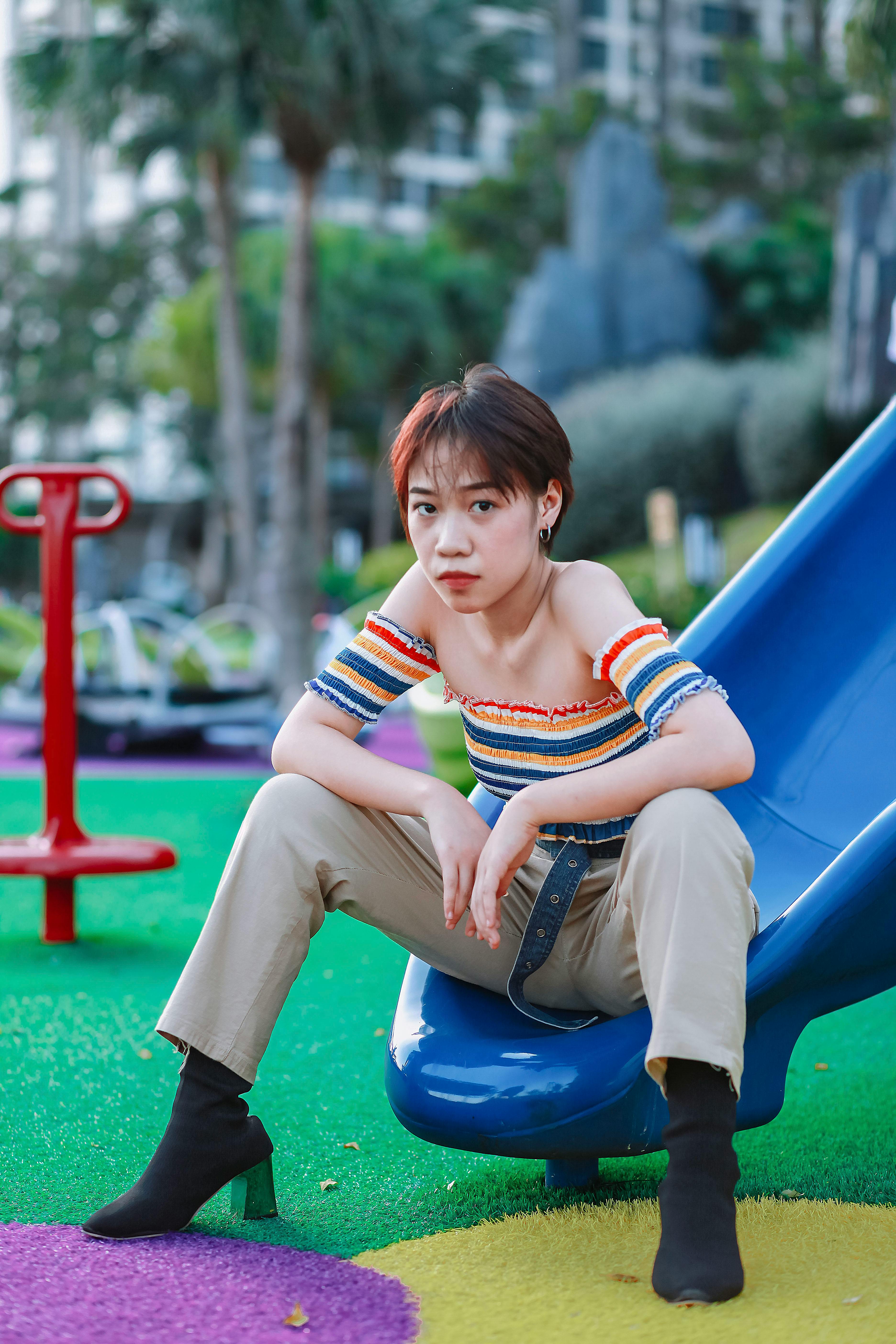Young Woman Sitting on Playground Slide Outdoors · Free Stock Photo