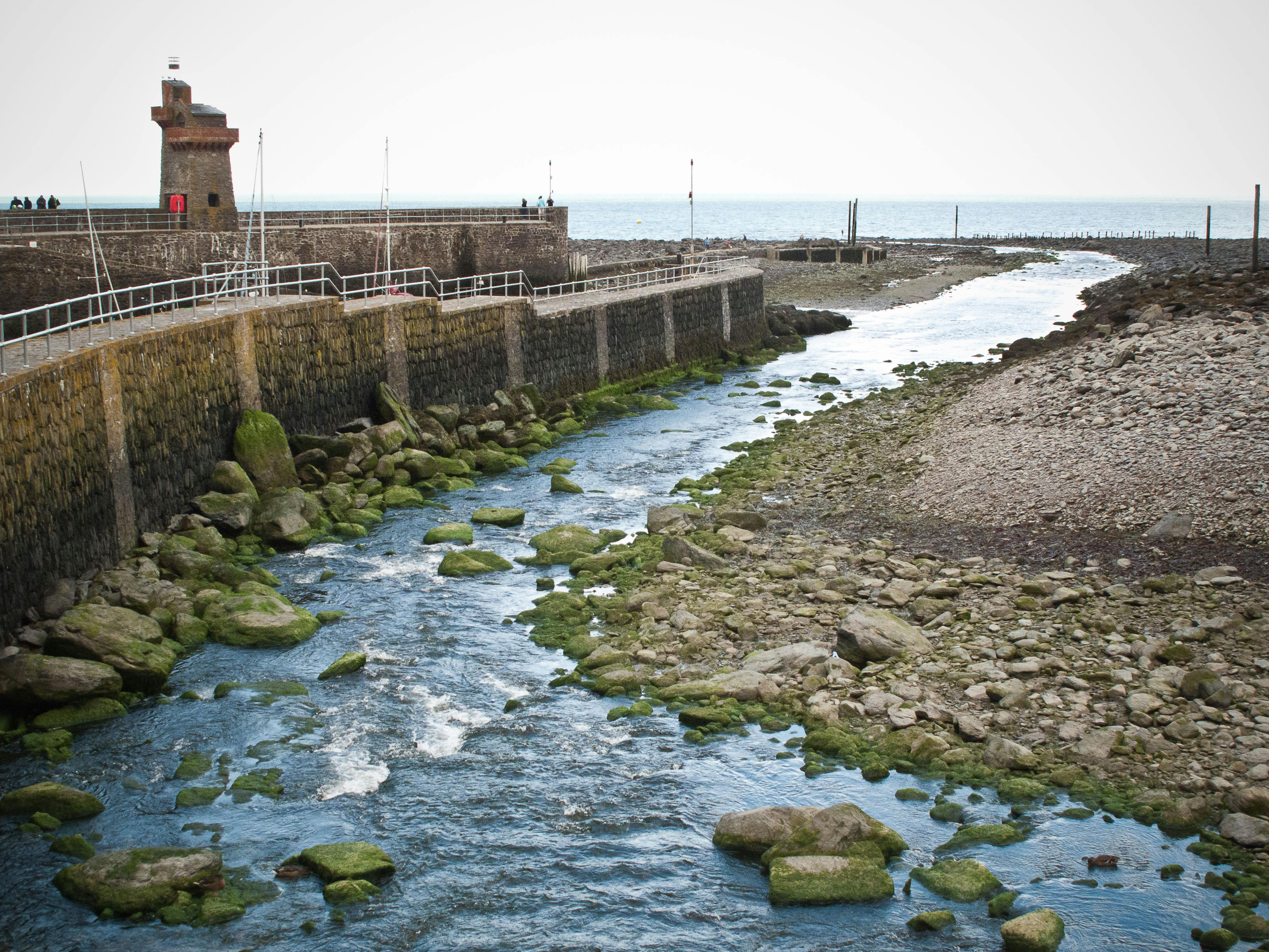 Scenic Seaside Pier with Flowing Stream · Free Stock Photo