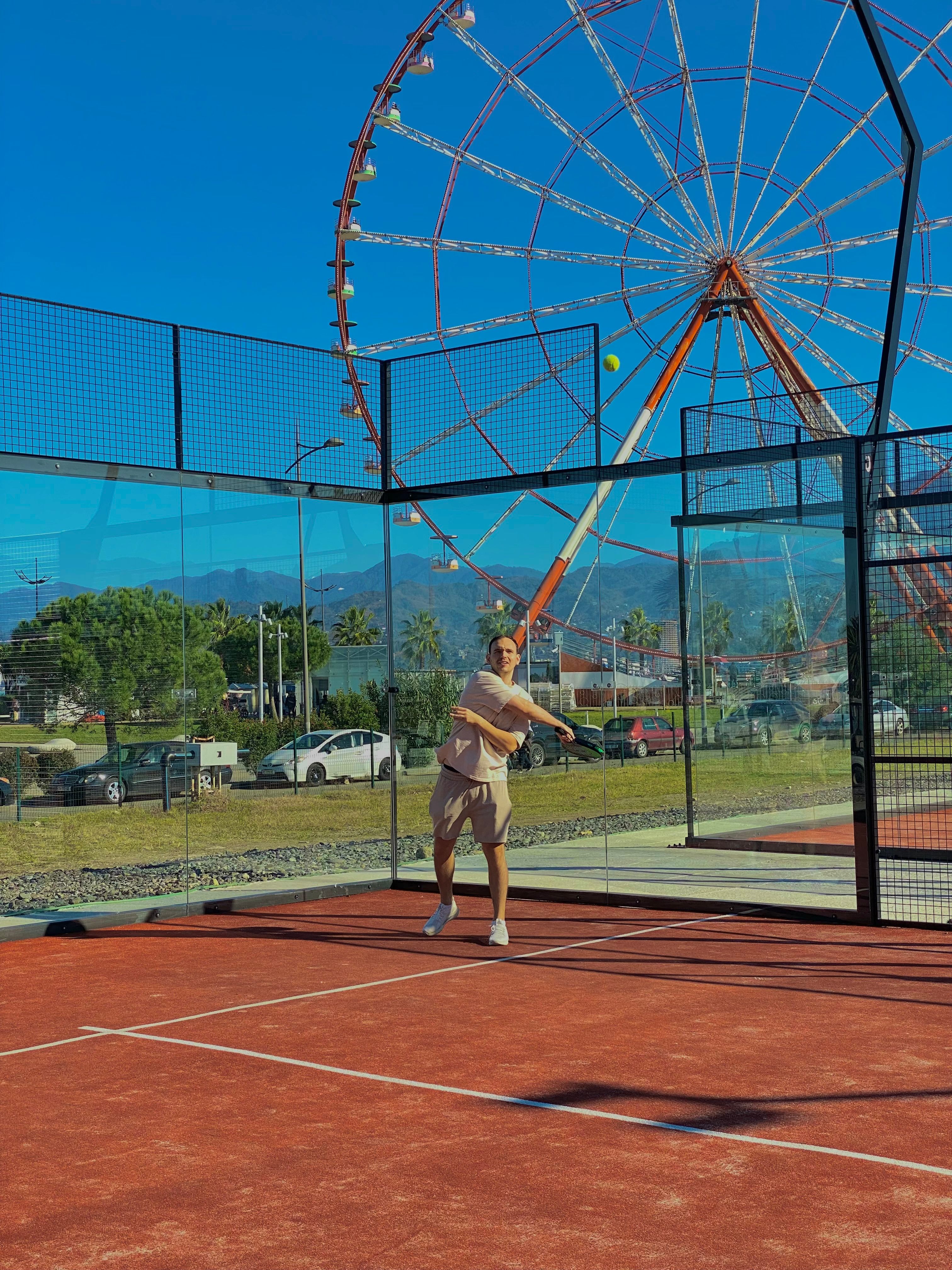 Tennis Player Against Ferris Wheel Backdrop · Free Stock Photo