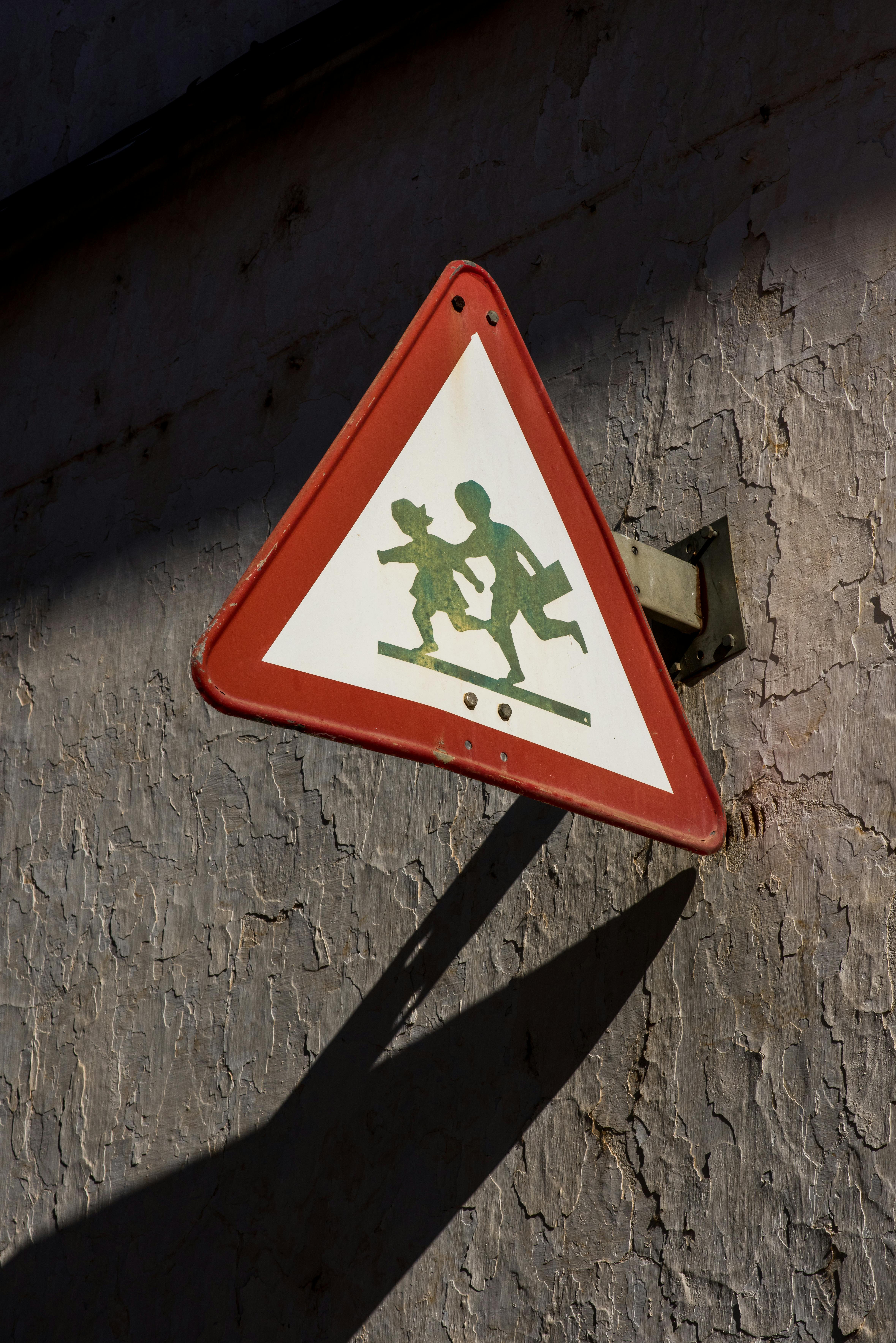 Children Crossing Warning Sign on Distressed Wall · Free Stock Photo
