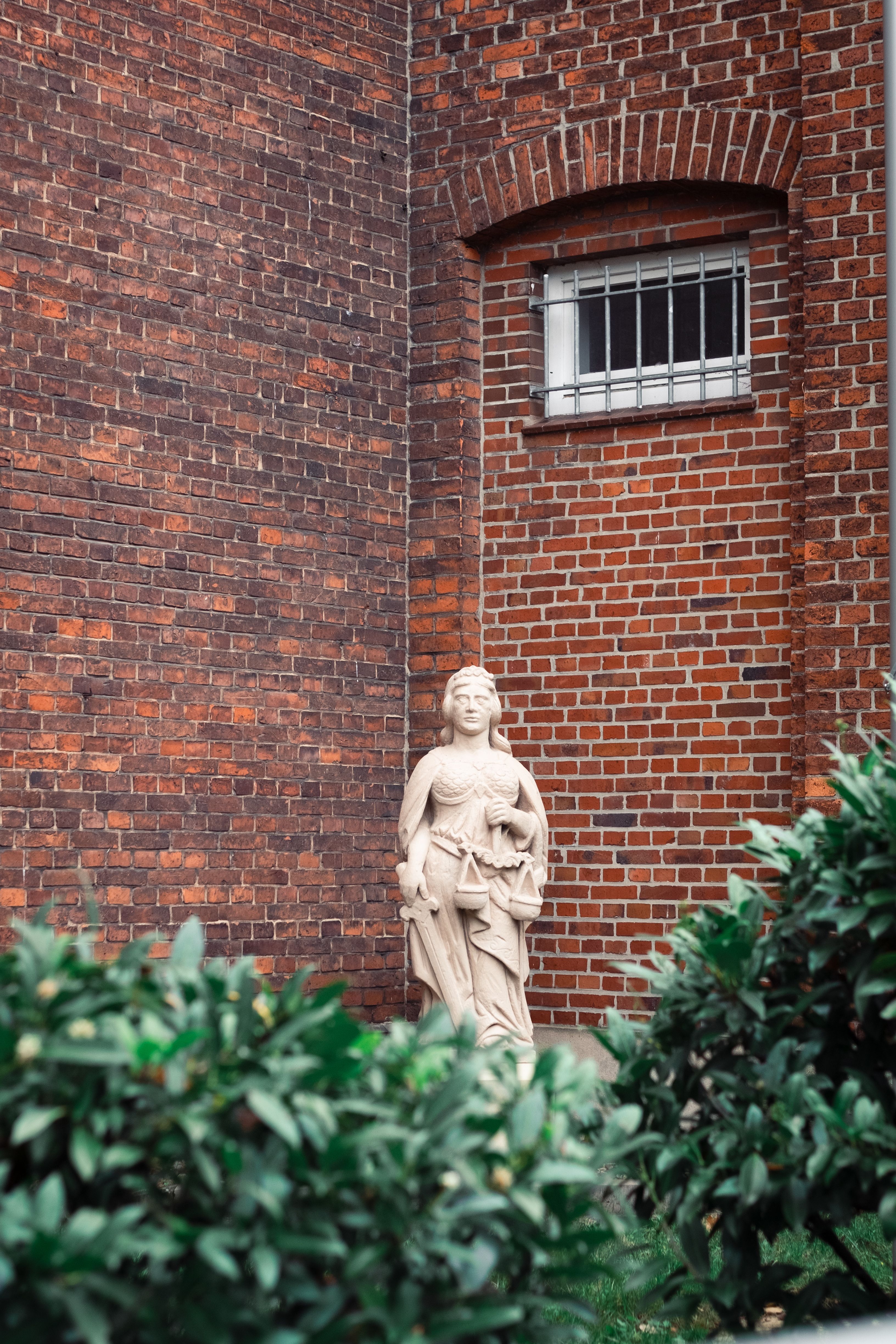 Elegant Stone Statue Amidst Historic Brick Architecture · Free Stock Photo