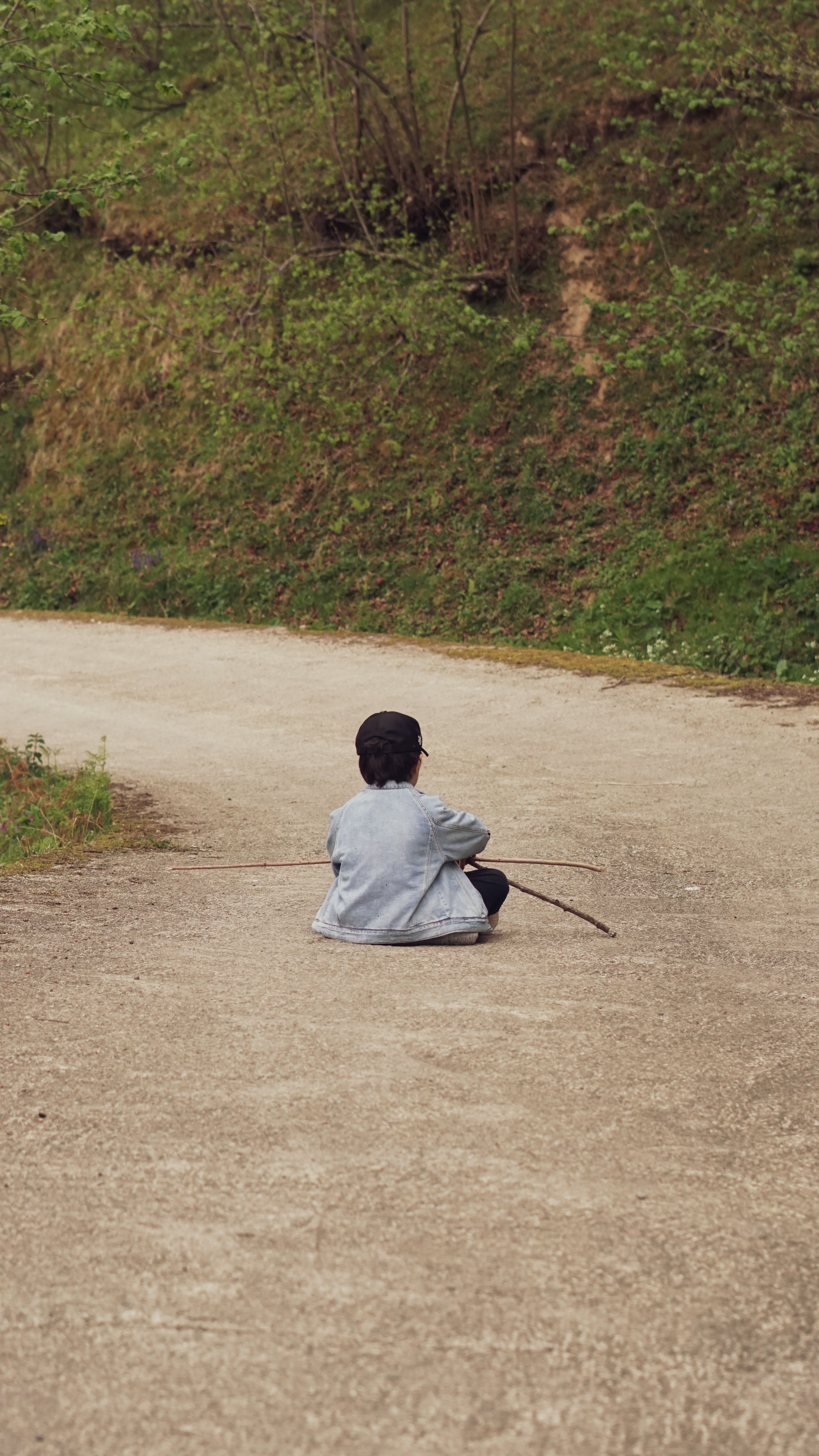 Solitary Child Sitting on a Quiet Roadside · Free Stock Photo