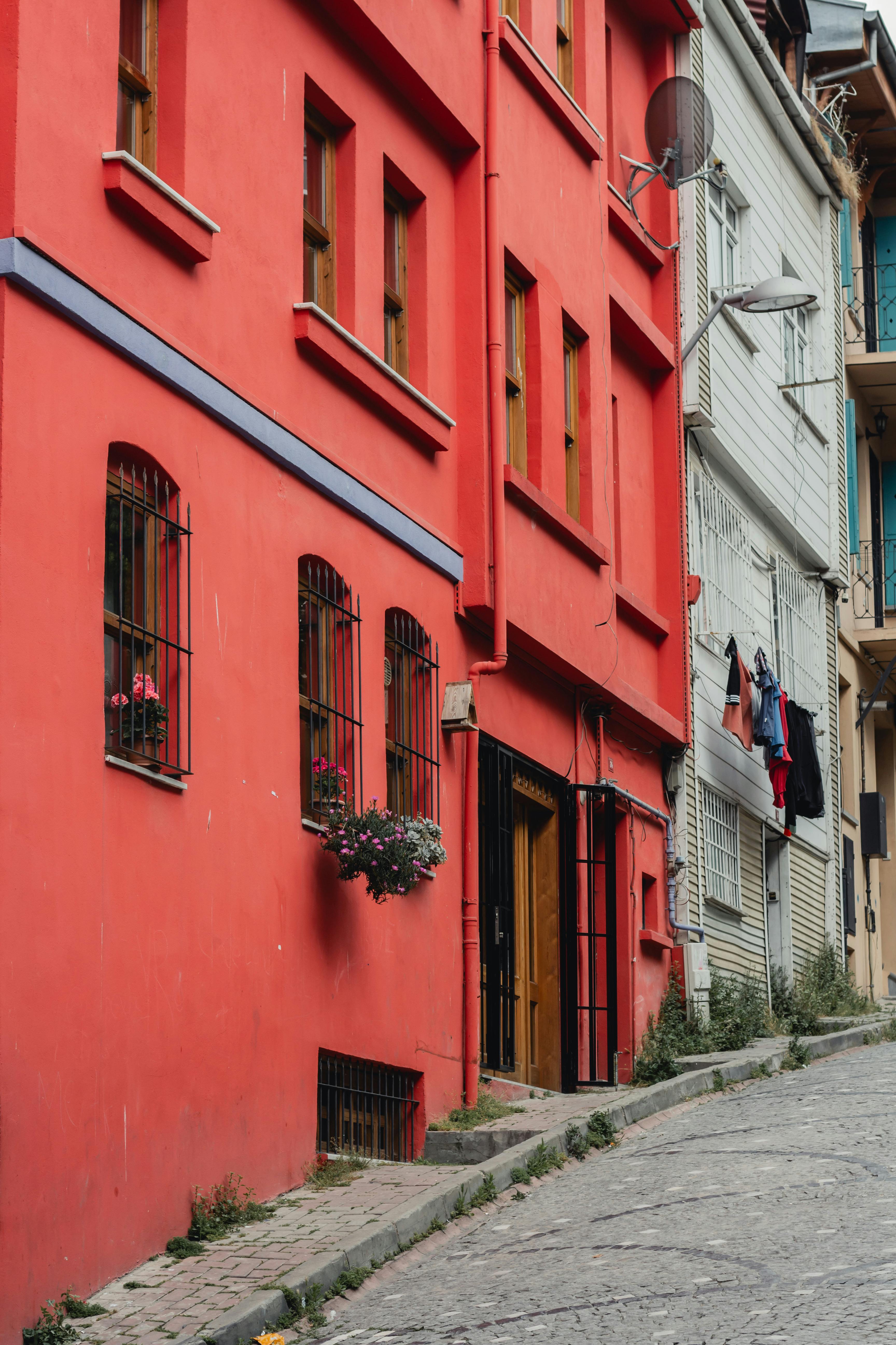 Colorful Urban Street with Vibrant Red Building Facade · Free Stock Photo