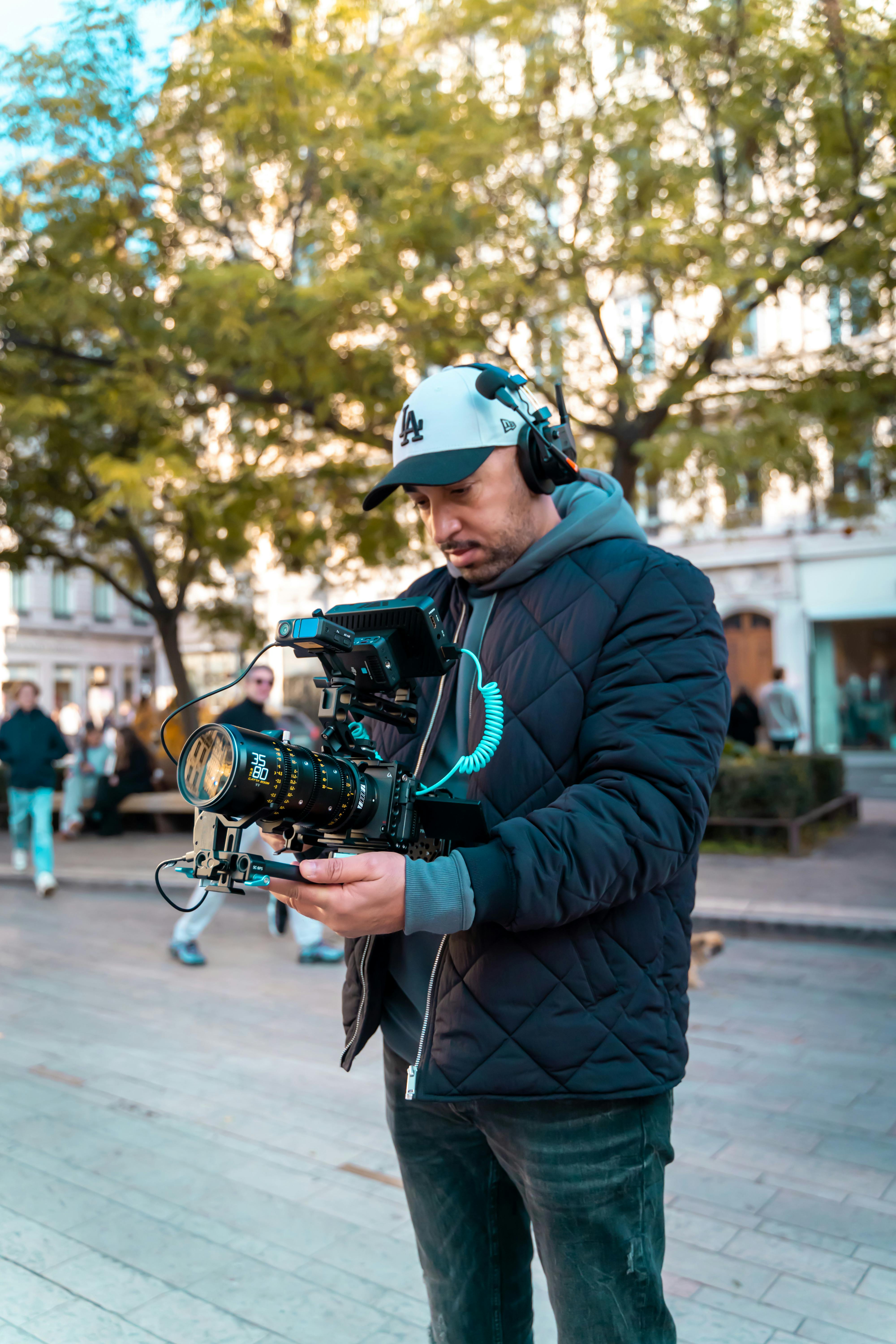 Filmmaker Operating Camera in Urban Park Setting · Free Stock Photo