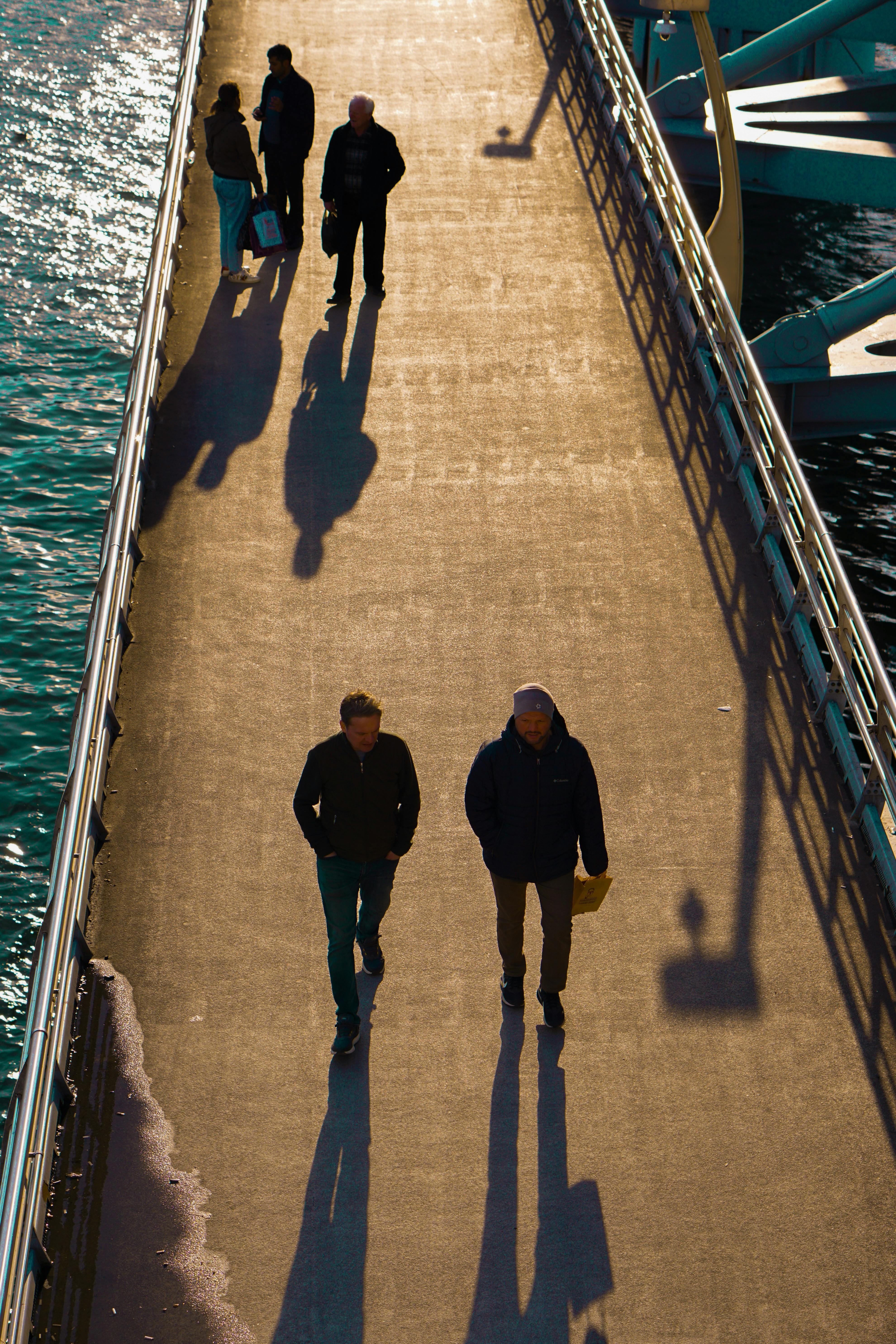 A Bridge Connecting Two Sides With People Walking Across Photos ...