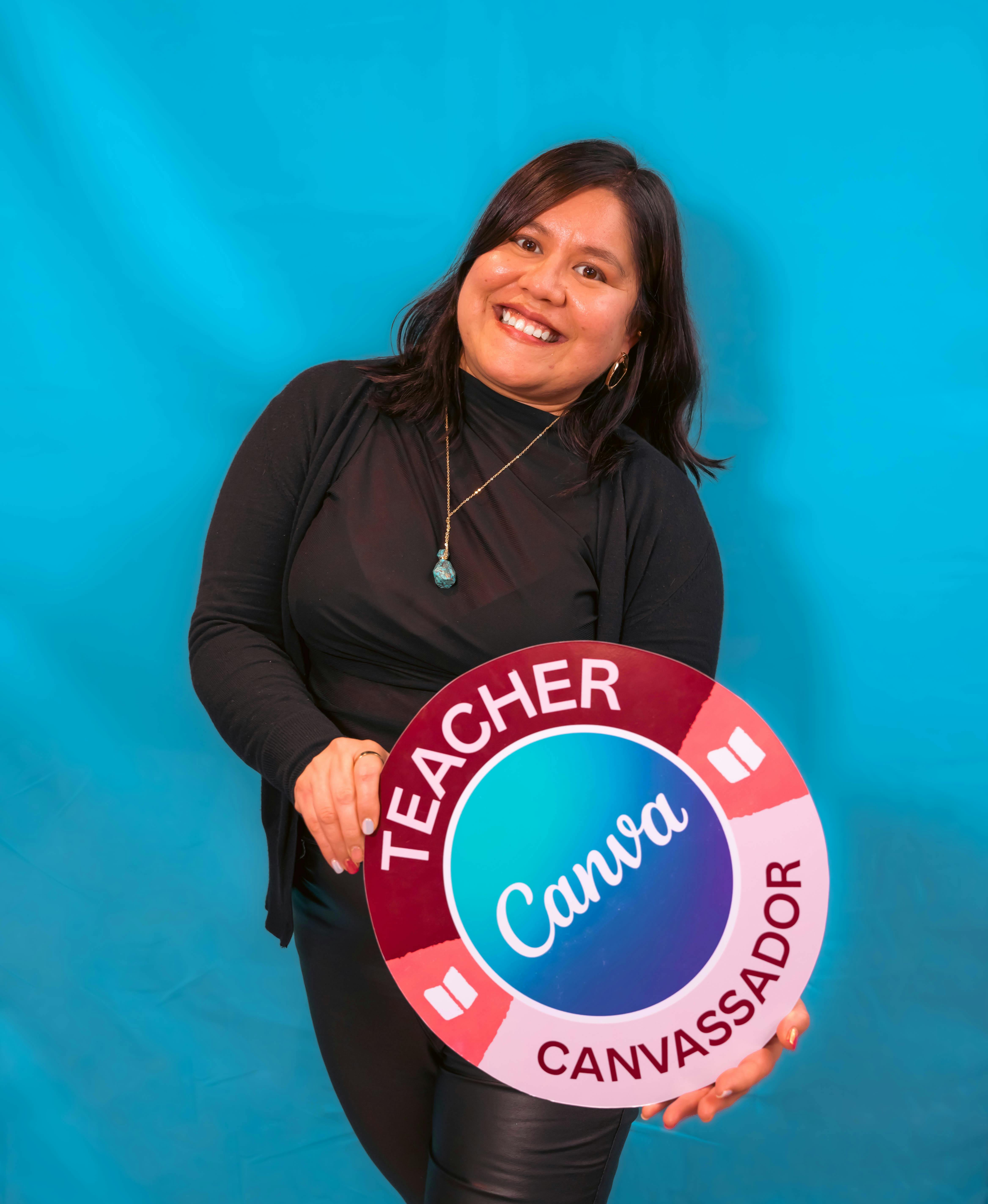 Smiling Teacher Holding Canva Ambassador Sign · Free Stock Photo