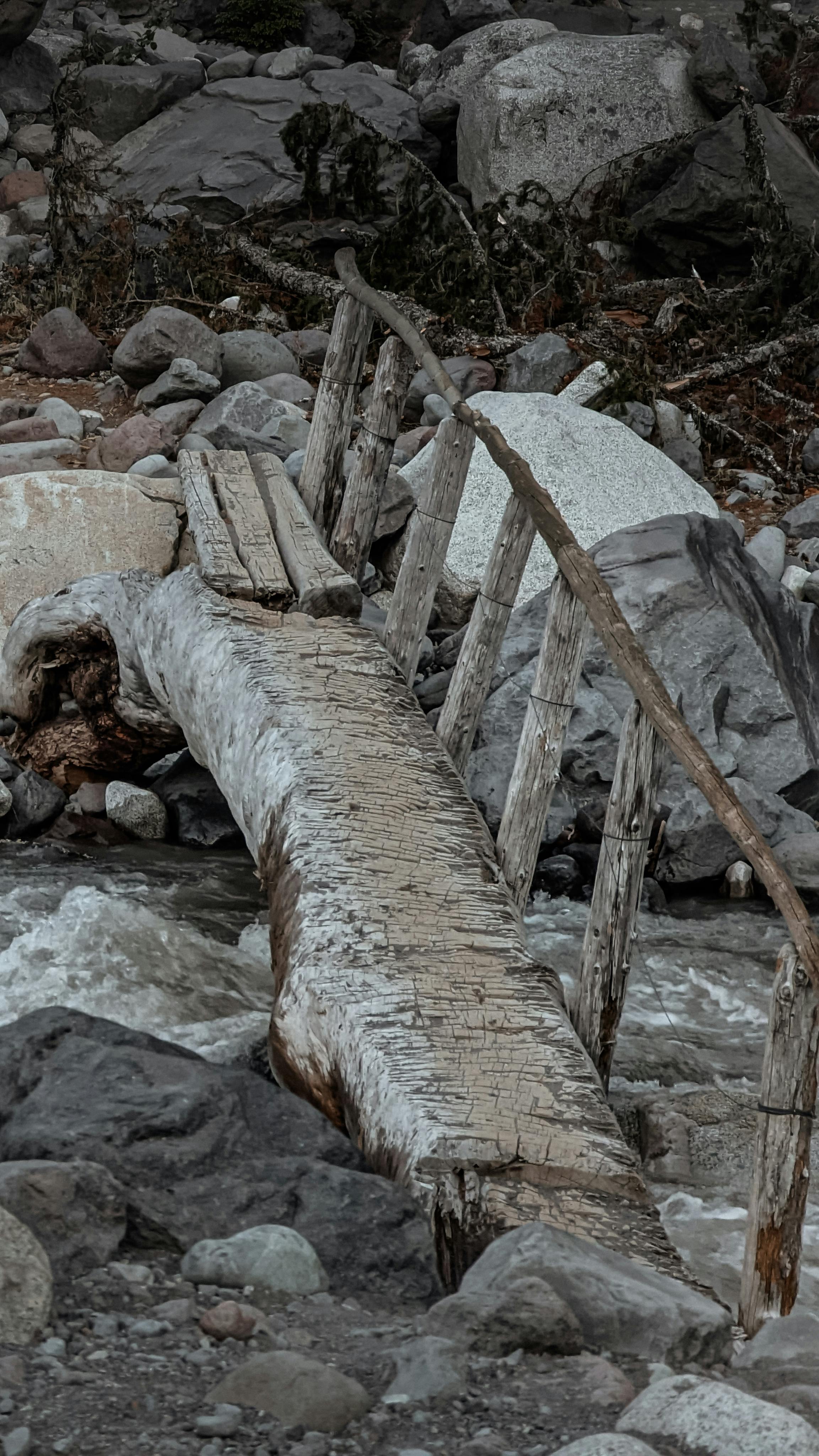 Rustic Wooden Bridge Over Rocky Stream · Free Stock Photo
