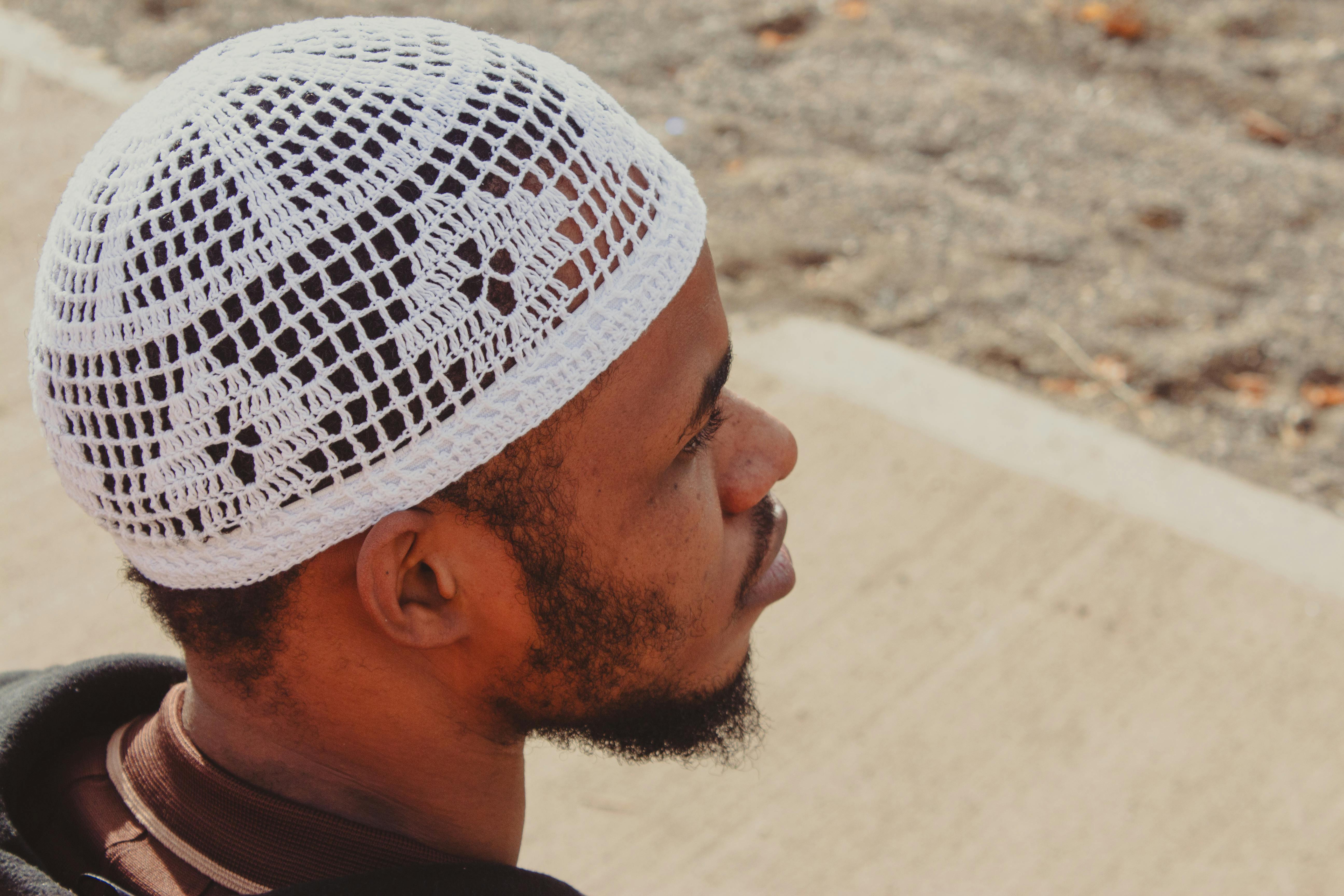 Contemplative Man with White Crocheted Cap Outdoors · Free Stock Photo