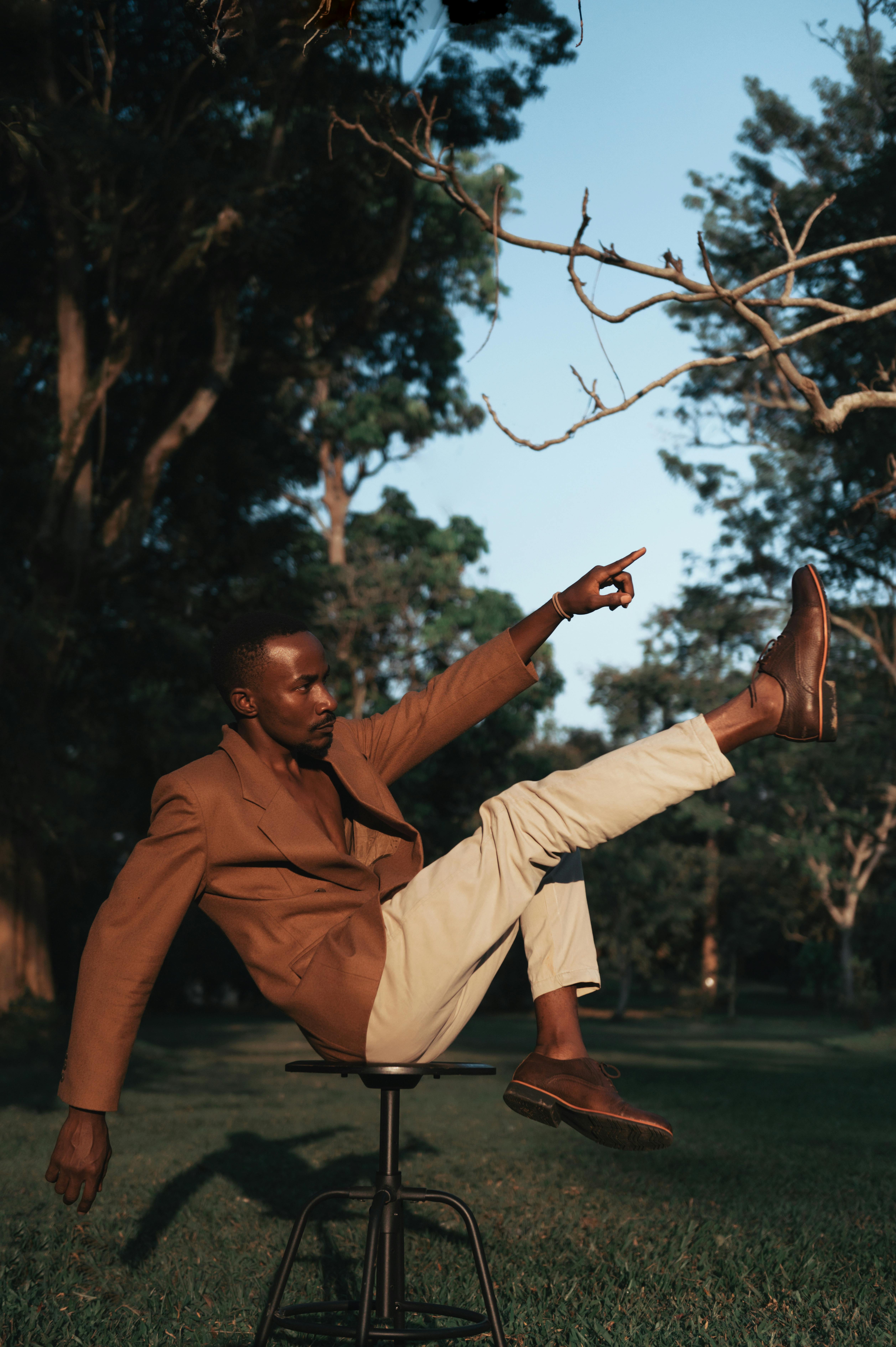 Stylish Man Balancing on Chair in Outdoor Setting · Free Stock Photo