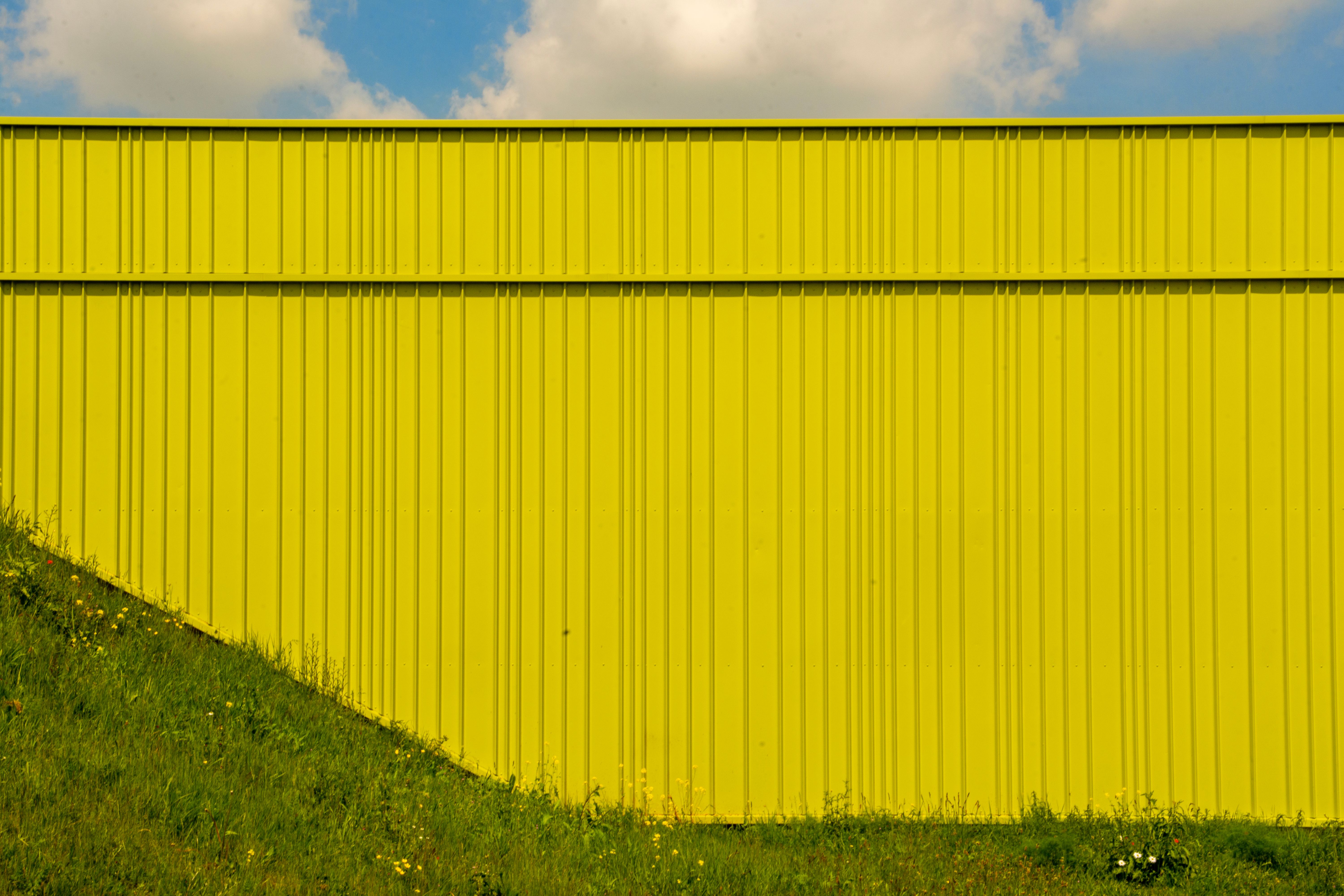 Vivid Yellow Metal Wall Against Blue Sky · Free Stock Photo