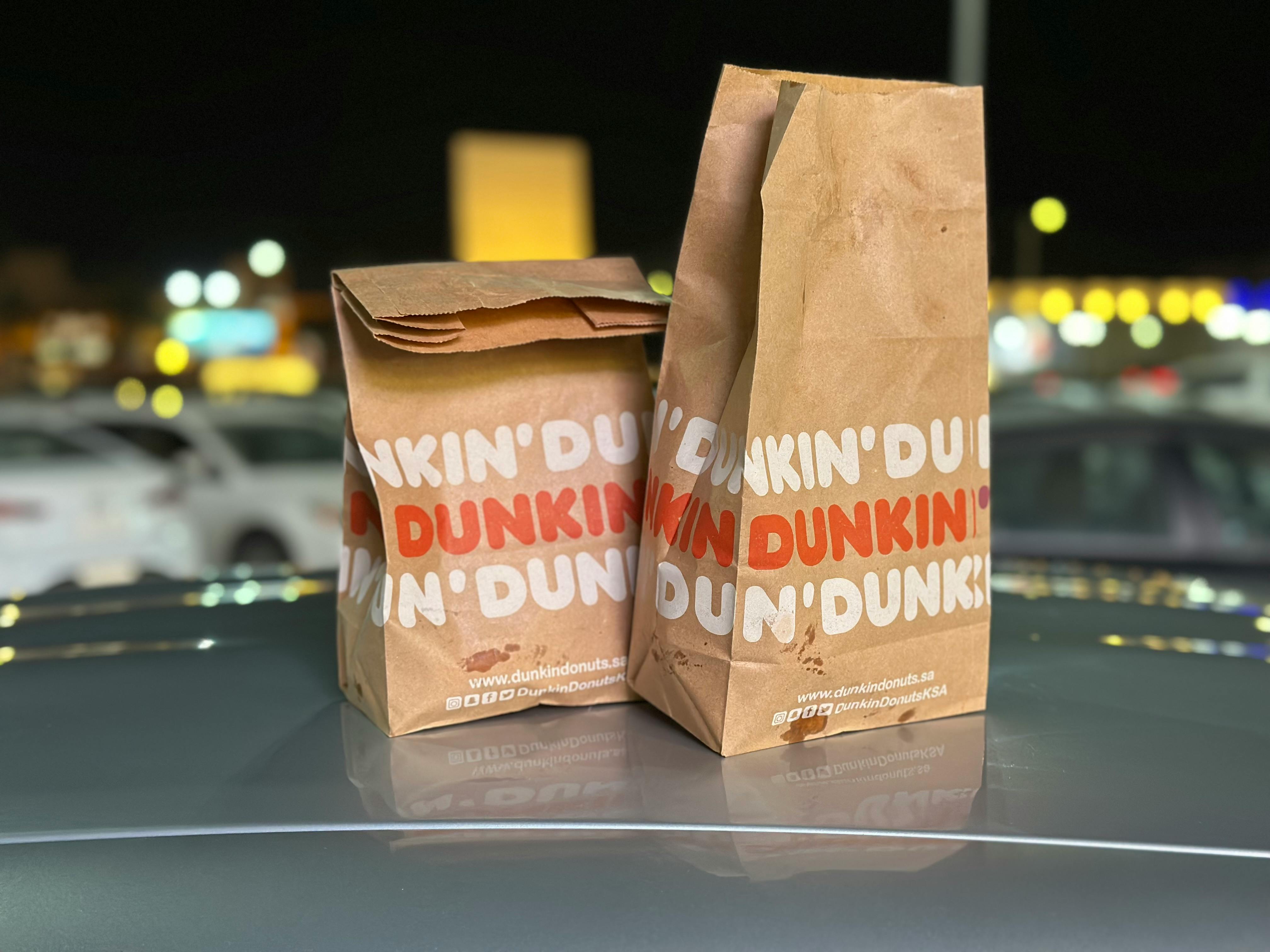 Dunkin' Donuts Bags on Car Hood at Night · Free Stock Photo