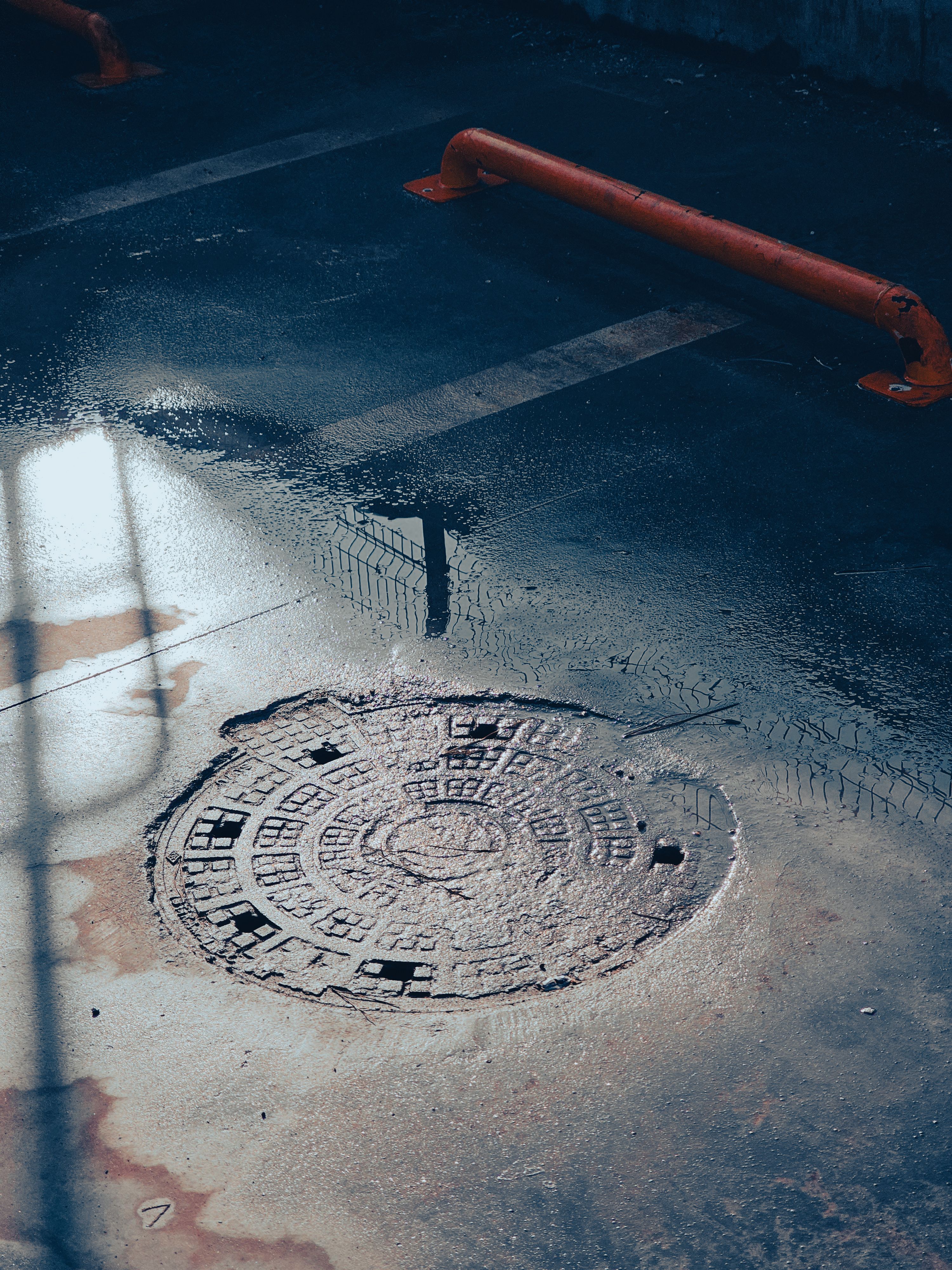 Urban Manhole Cover in Sunlit Parking Lot · Free Stock Photo