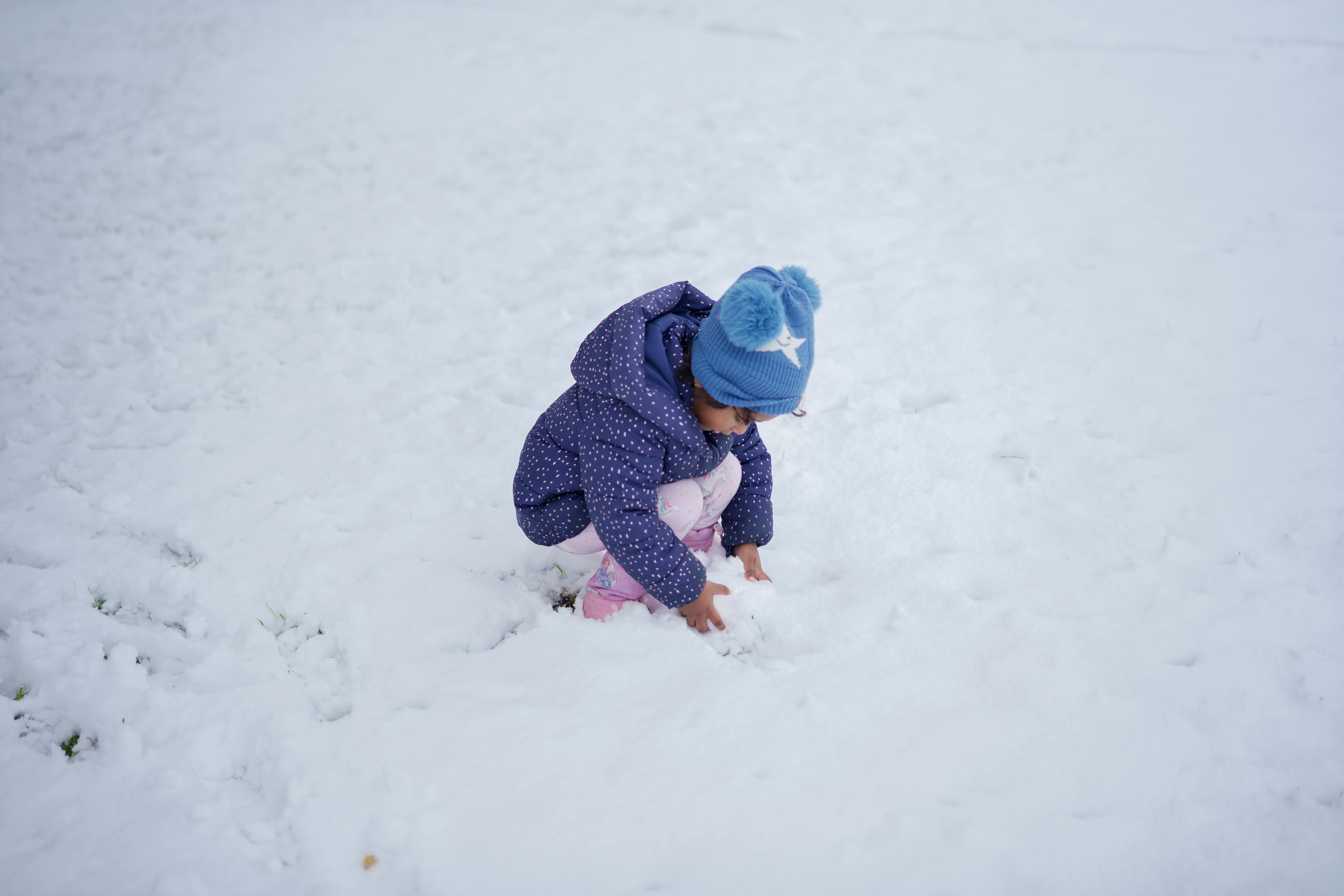 Child playing in snow, winter clothing, outdoors · Free Stock Photo