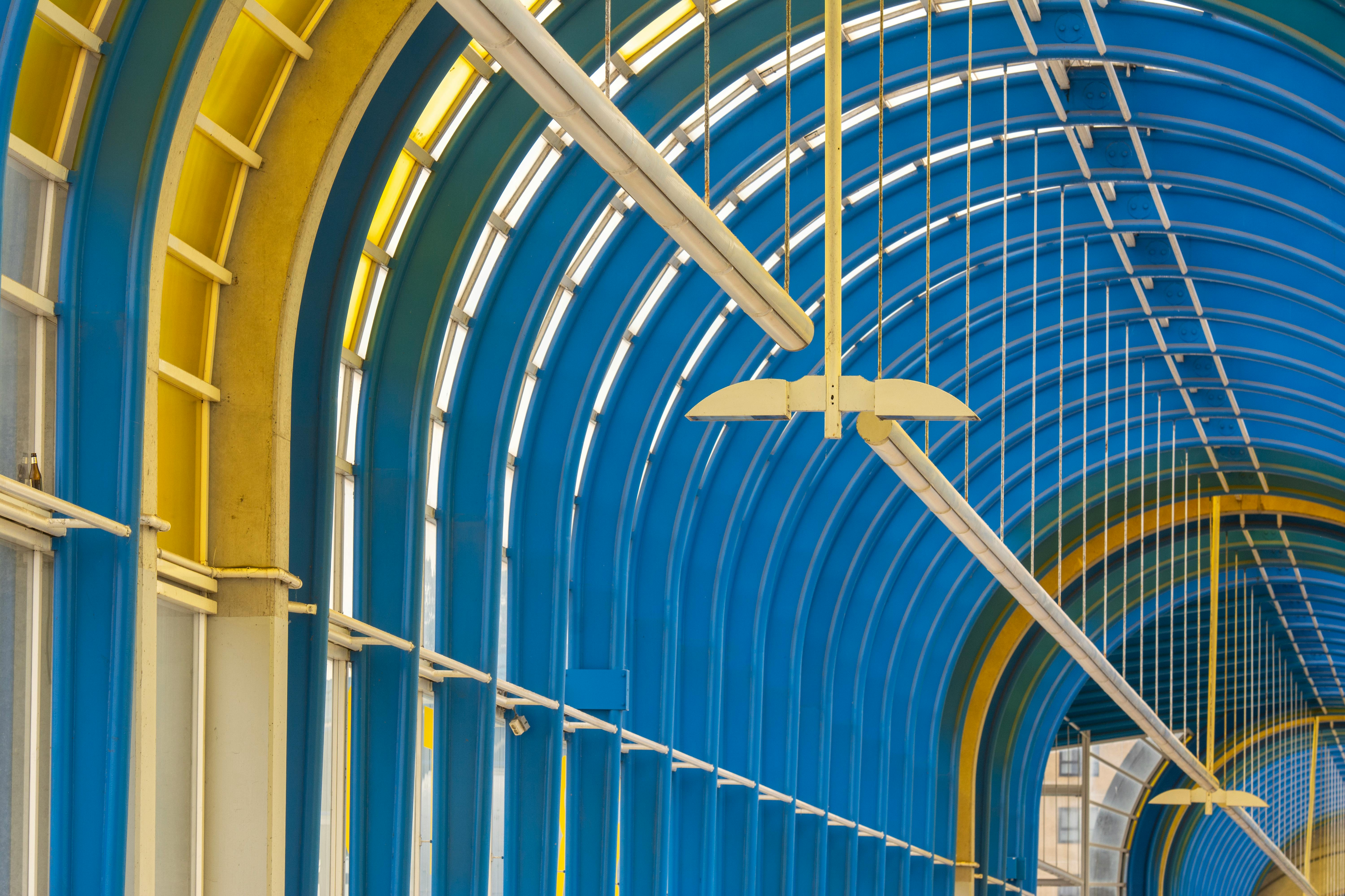 Vibrant Blue and Yellow Arched Walkway Architecture · Free Stock Photo