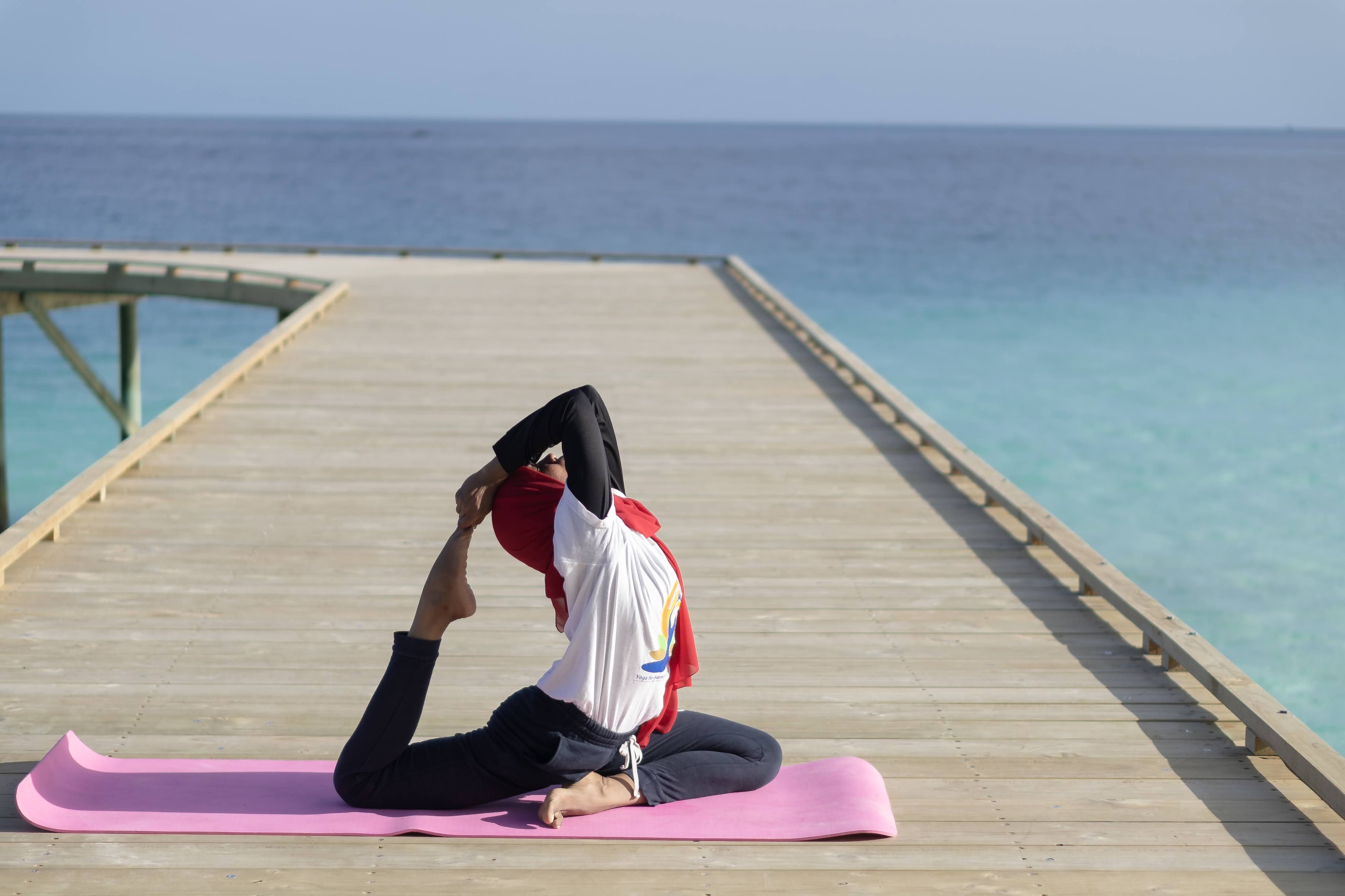 Yoga Pose on Serene Ocean Pier Under Blue Sky · Free Stock Photo