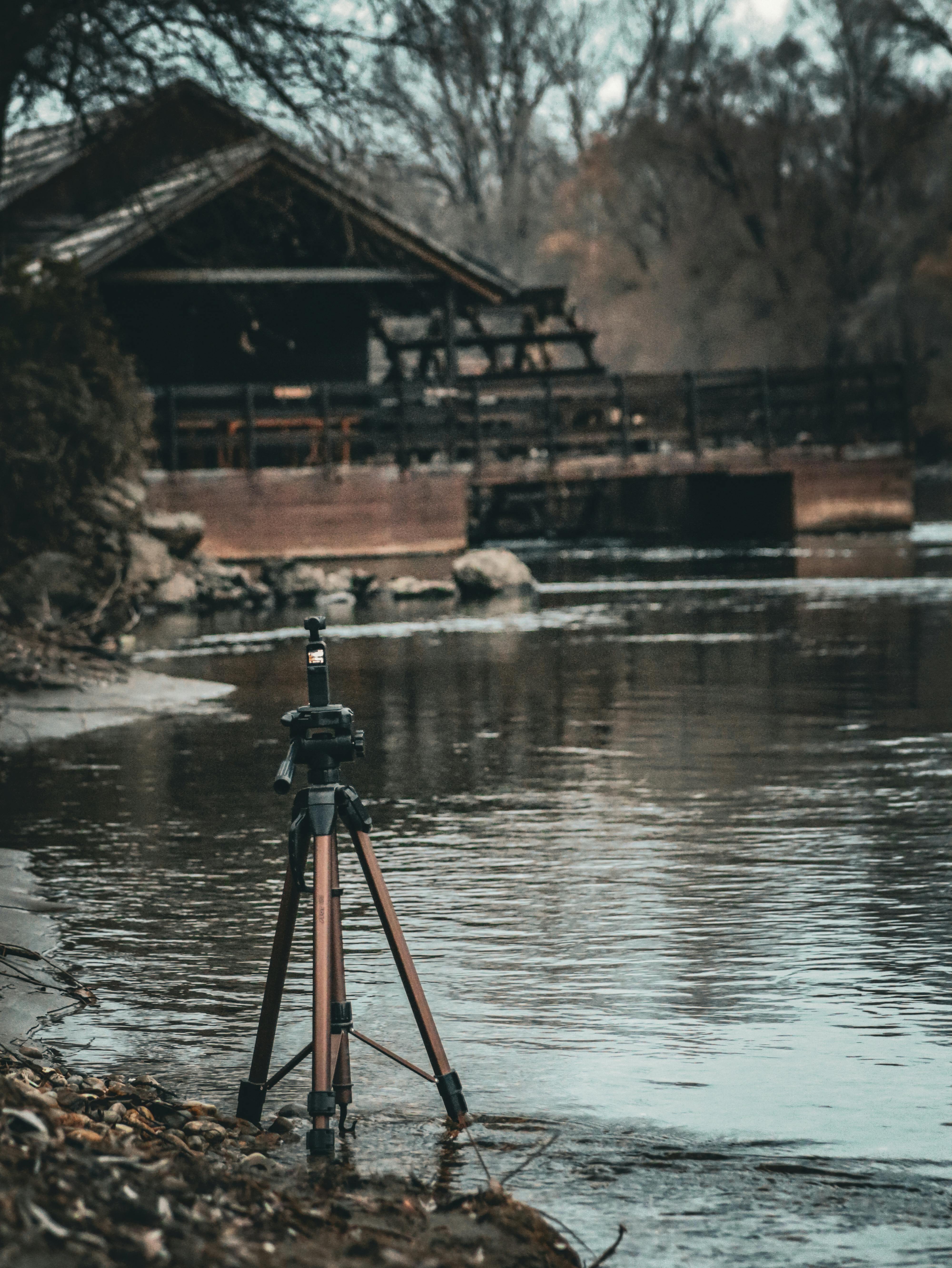 Rustic Cabin by Riverside with Tripod Setup · Free Stock Photo