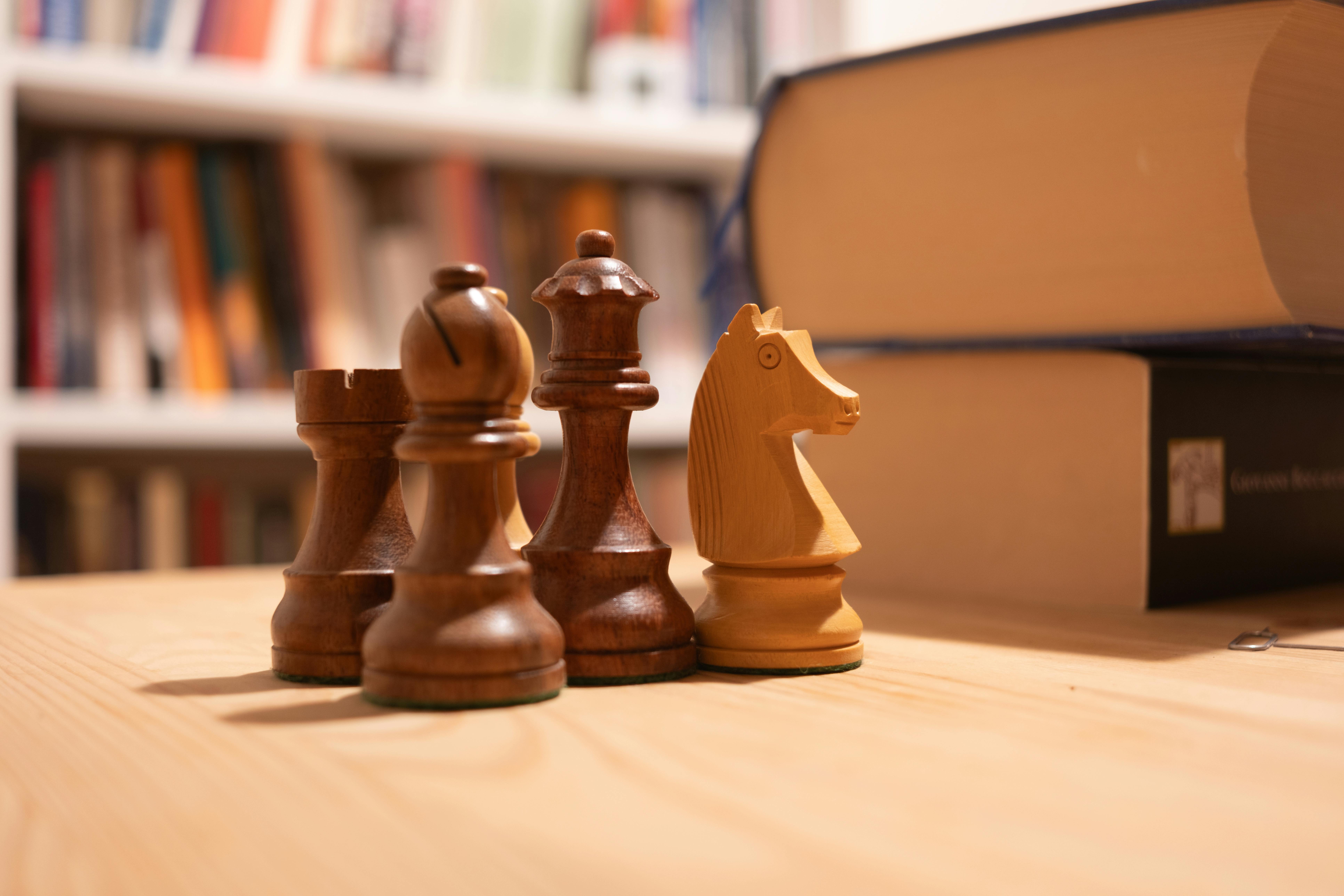Chess Pieces on Wooden Table with Bookshelf · Free Stock Photo