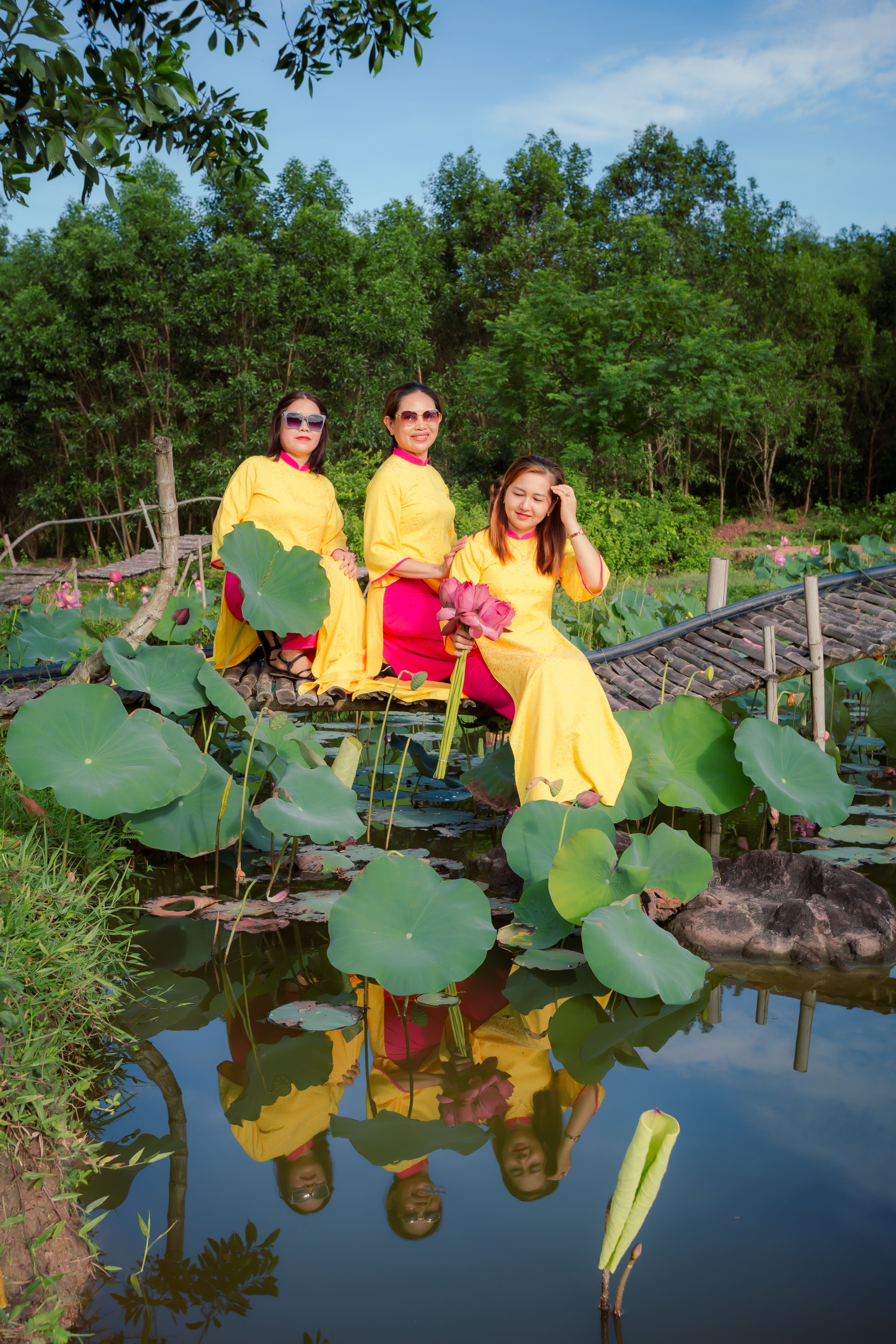 Women in Traditional Ao Dai Posing in Lotus Garden · Free Stock Photo
