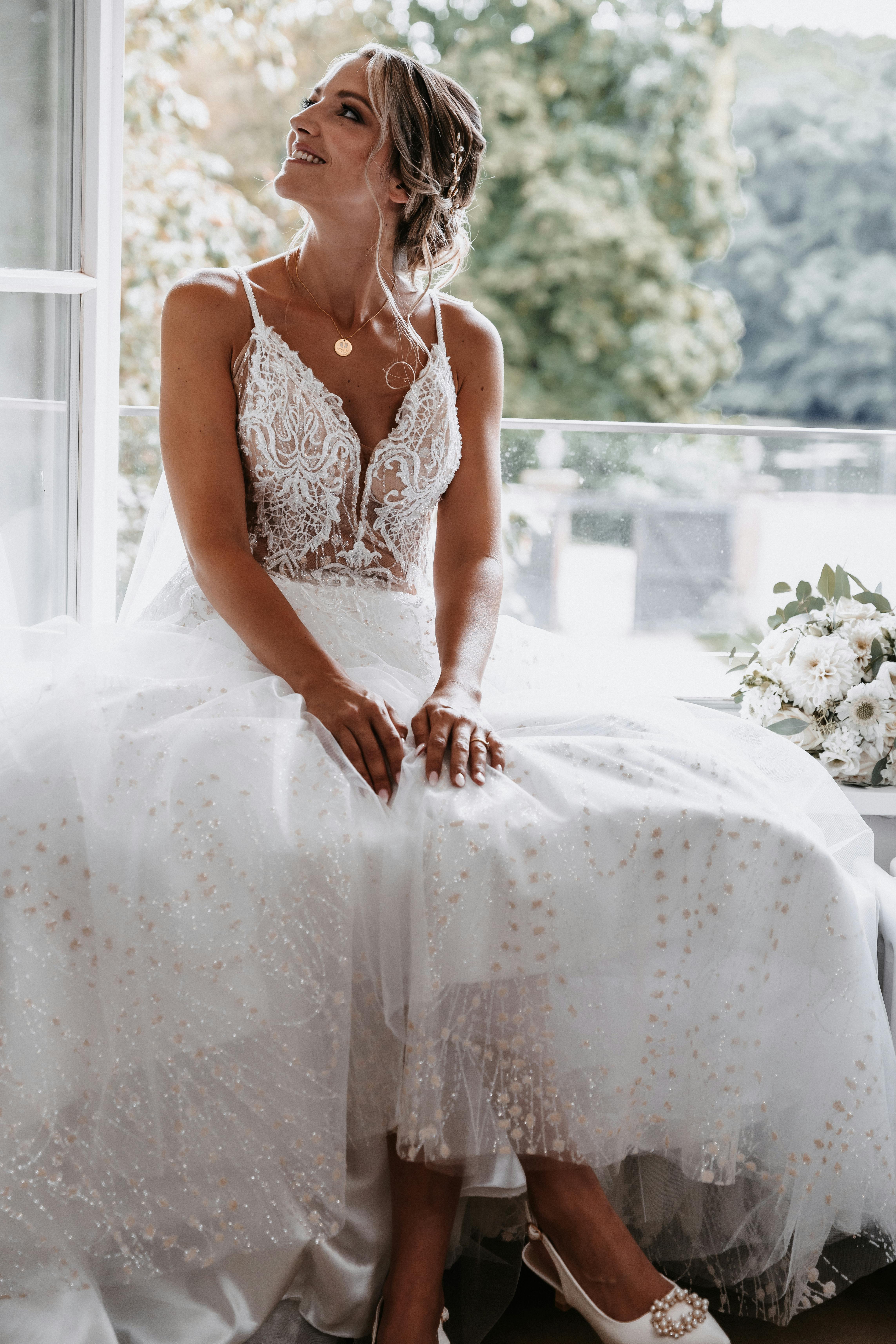 Bride Sitting by Window in Elegant Wedding Dress · Free Stock Photo