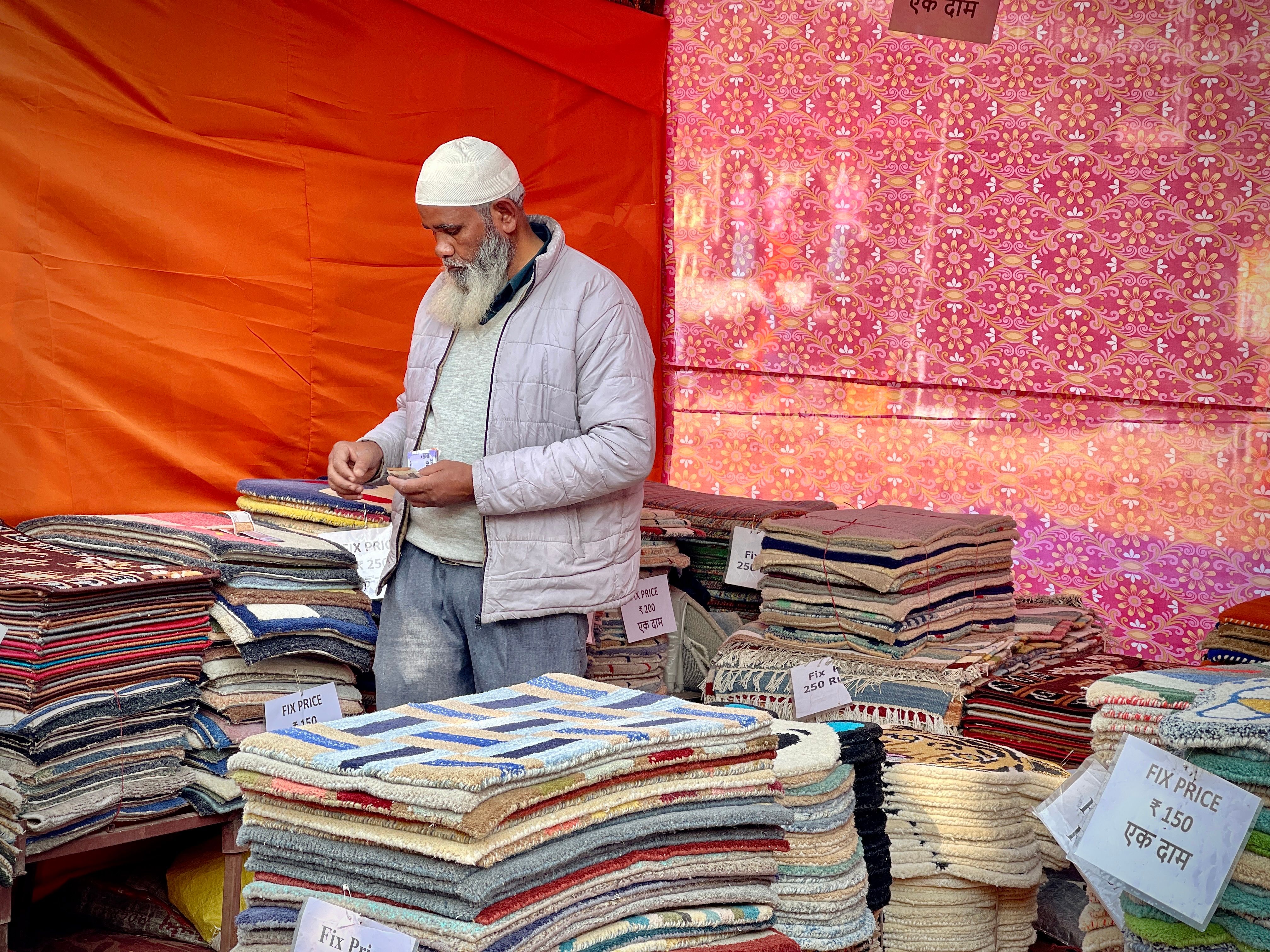 Market Vendor Selling Colorful Rugs at Street Bazaar · Free Stock Photo