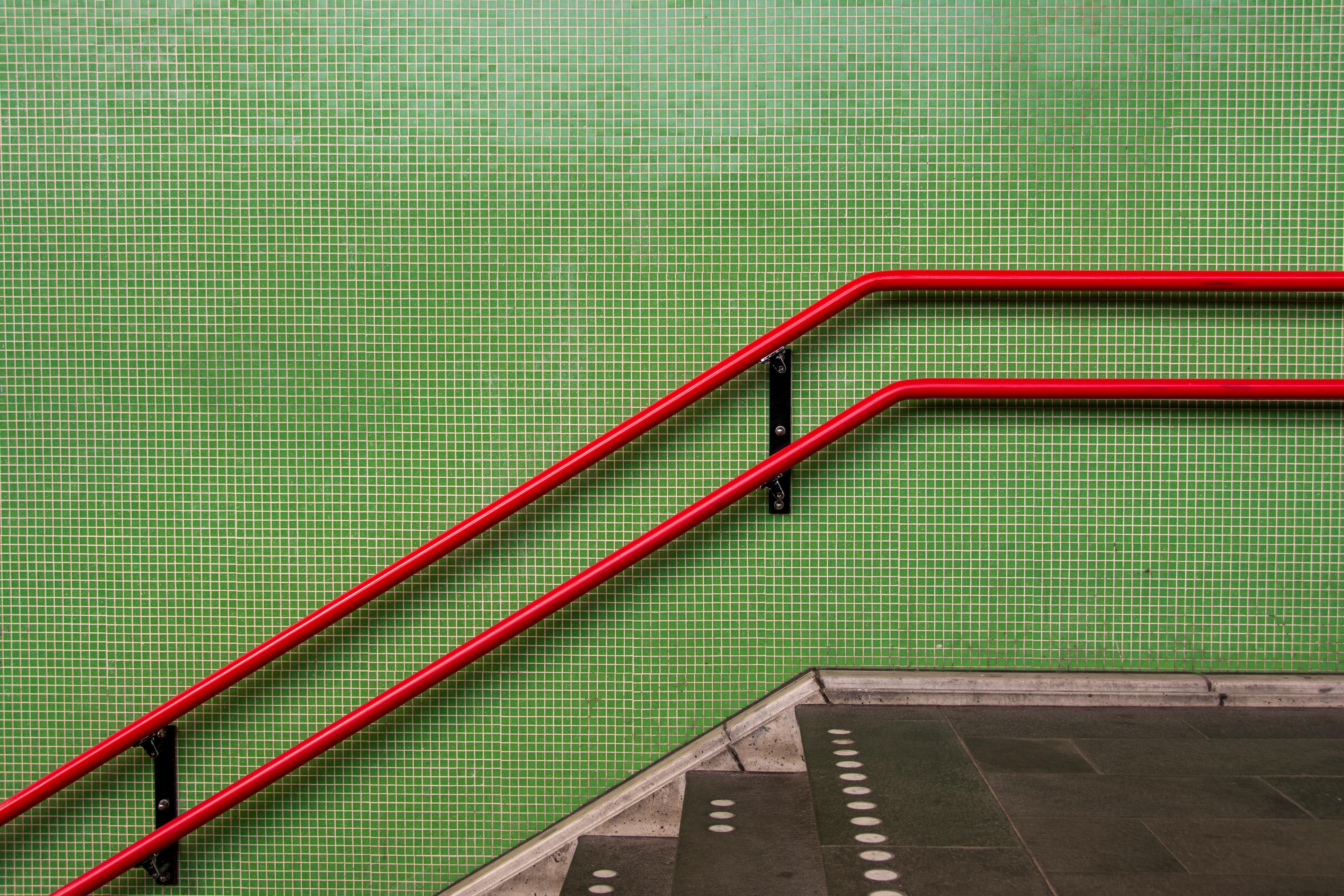 Vibrant Red Handrail on Green Tiled Wall · Free Stock Photo