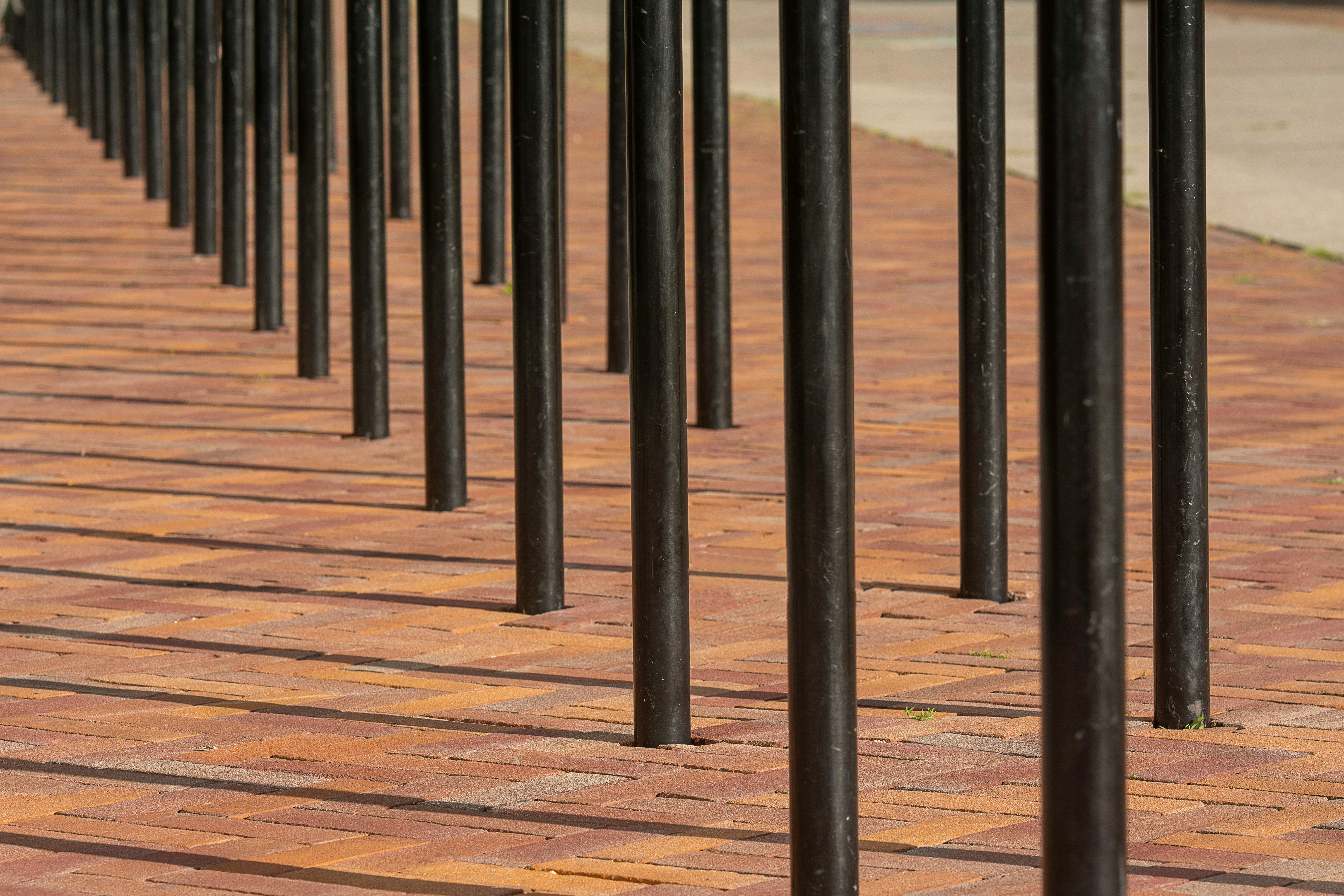 Artistic Perspective of Black Metal Poles on Brick Path · Free Stock Photo